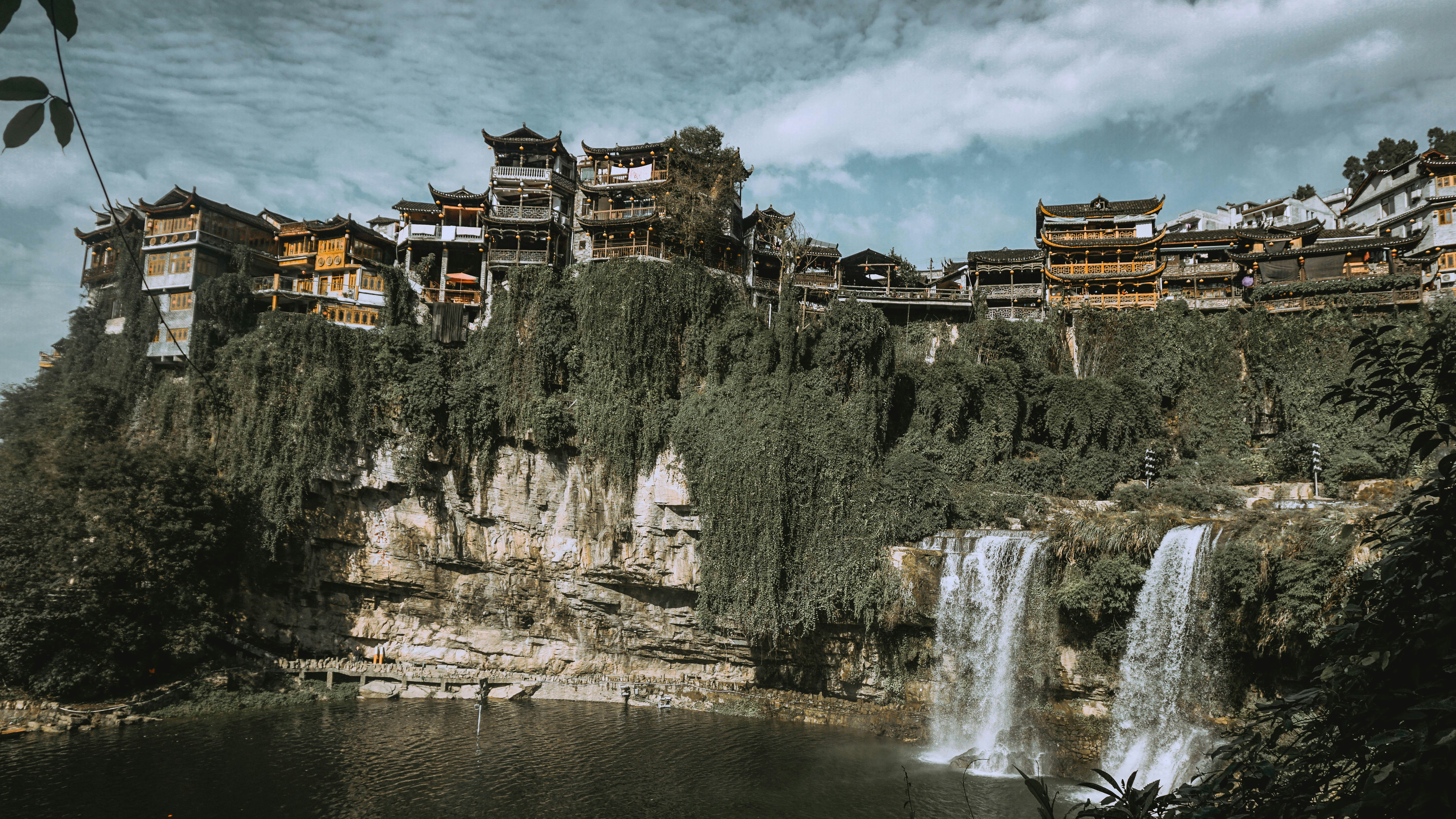 Waterfalls under high-rise buildings in mountain cliff photo – Free ...
