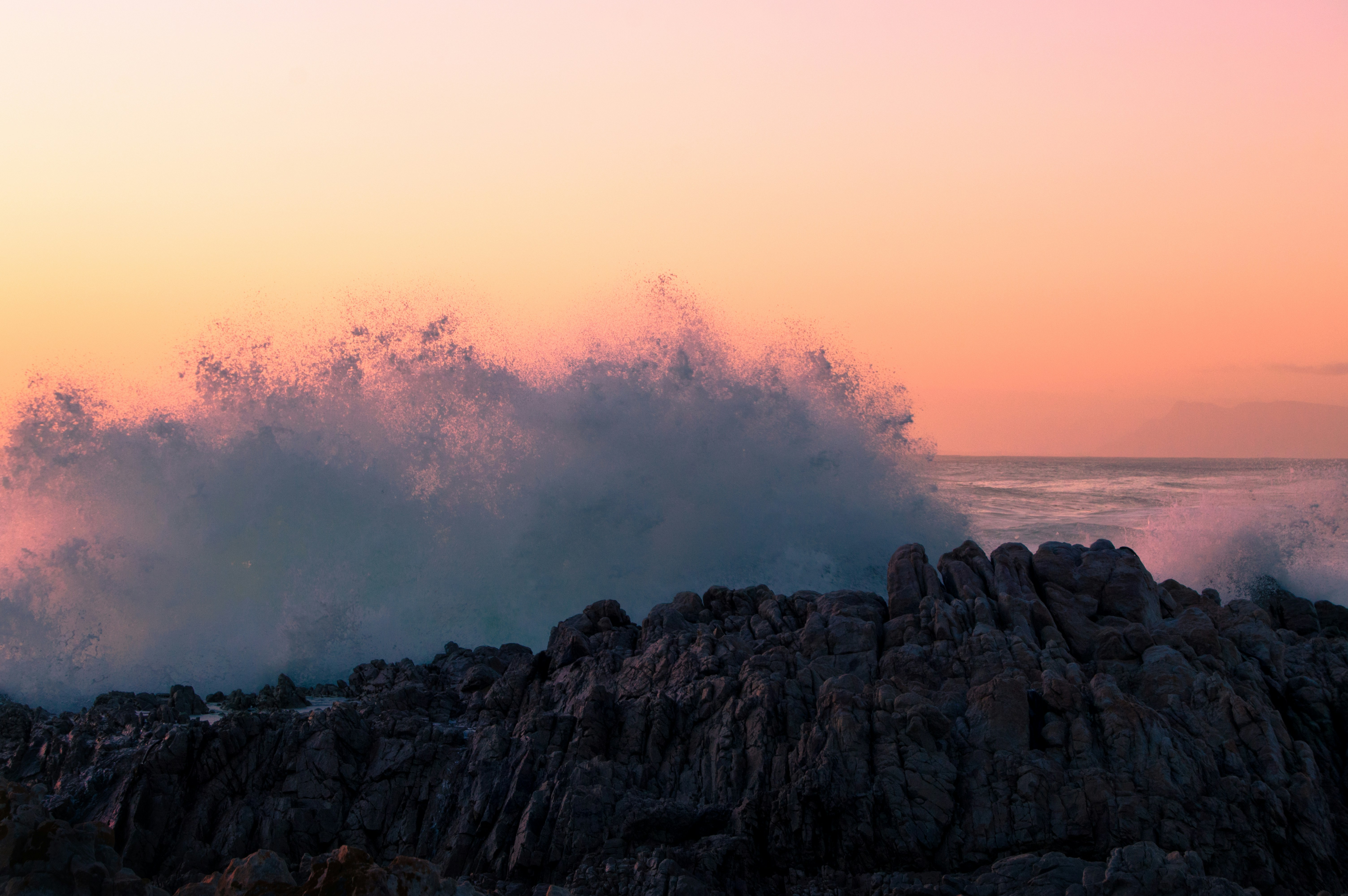 Sunset Clash: Crashing Crest Against Jagged Shoreline
