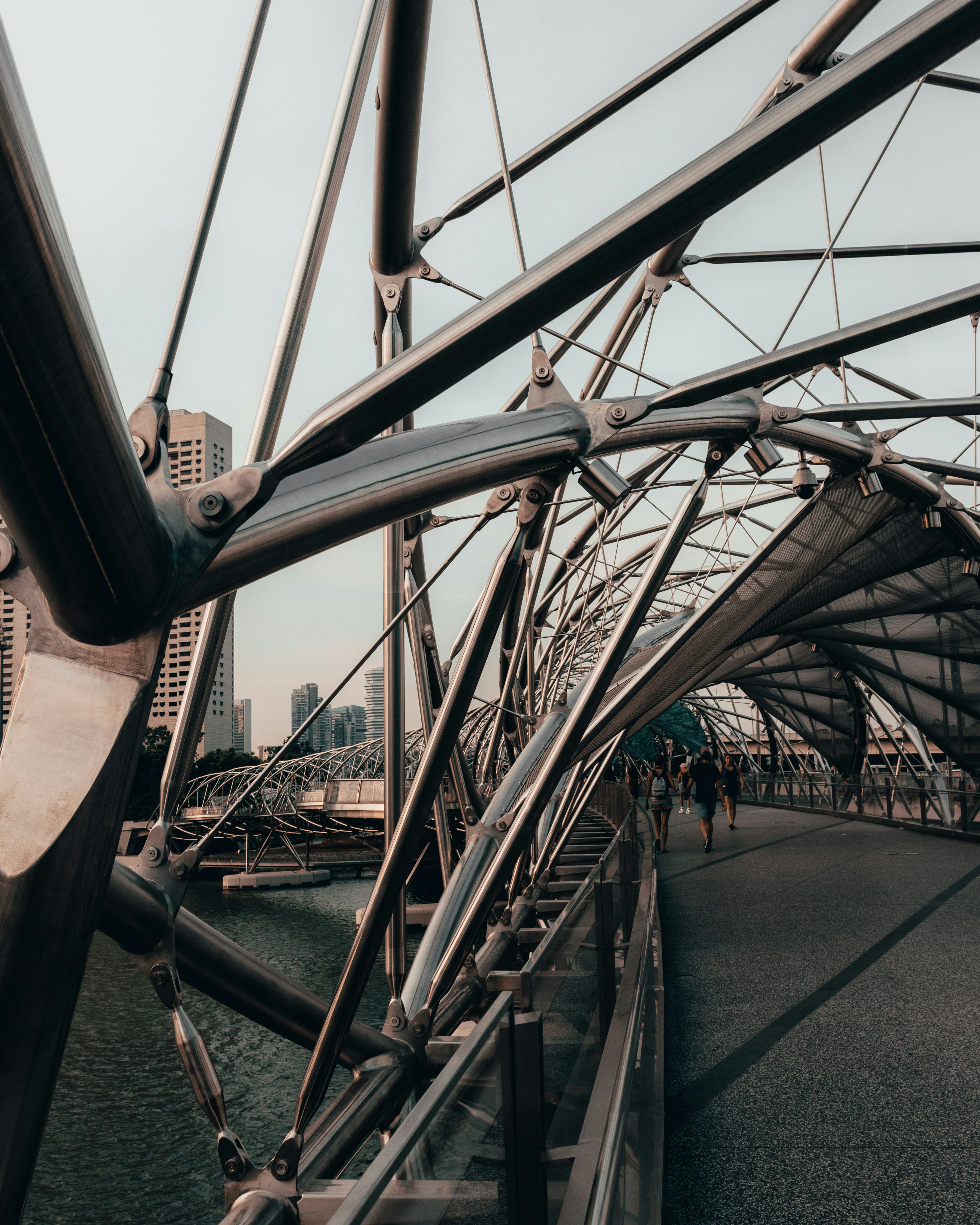 Modern bridge structure showcasing intricate steel framework with pedestrians walking along the path.