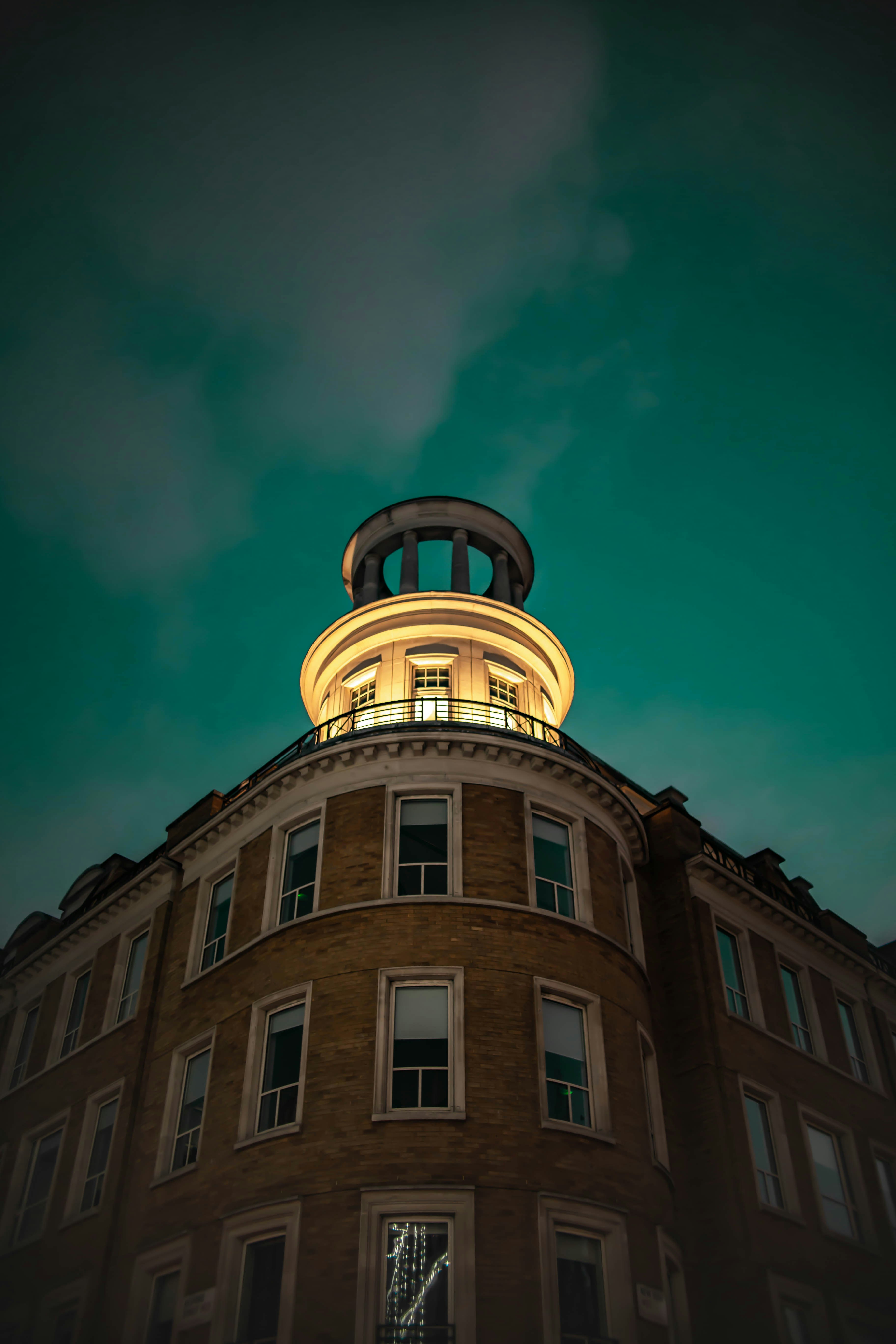 Amber Crown Over Brick Curvature: Night Turret Illuminates a Corner Building