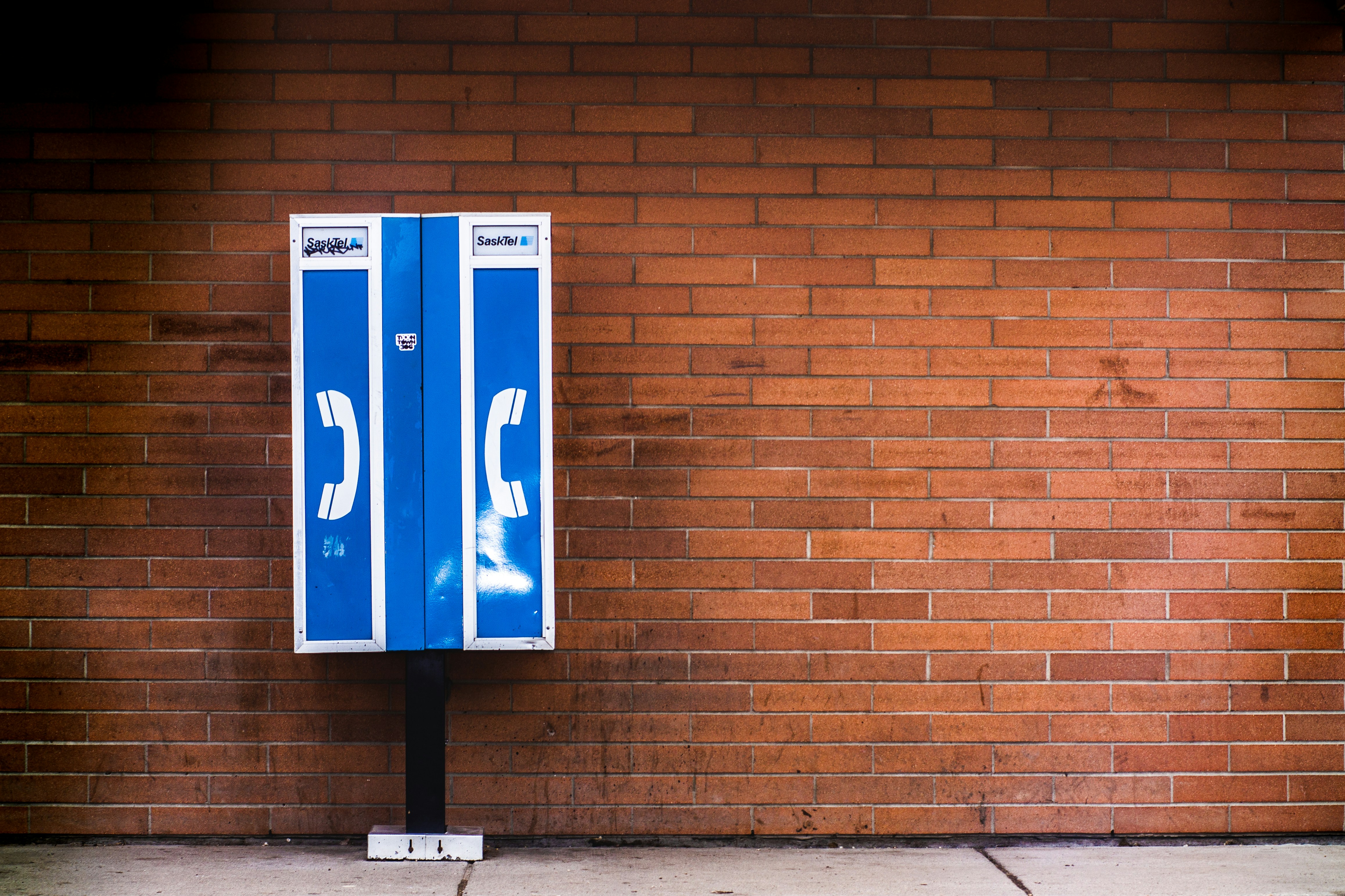 Twin Blue Payphones Framed by a Brick-Walled Urban Stage