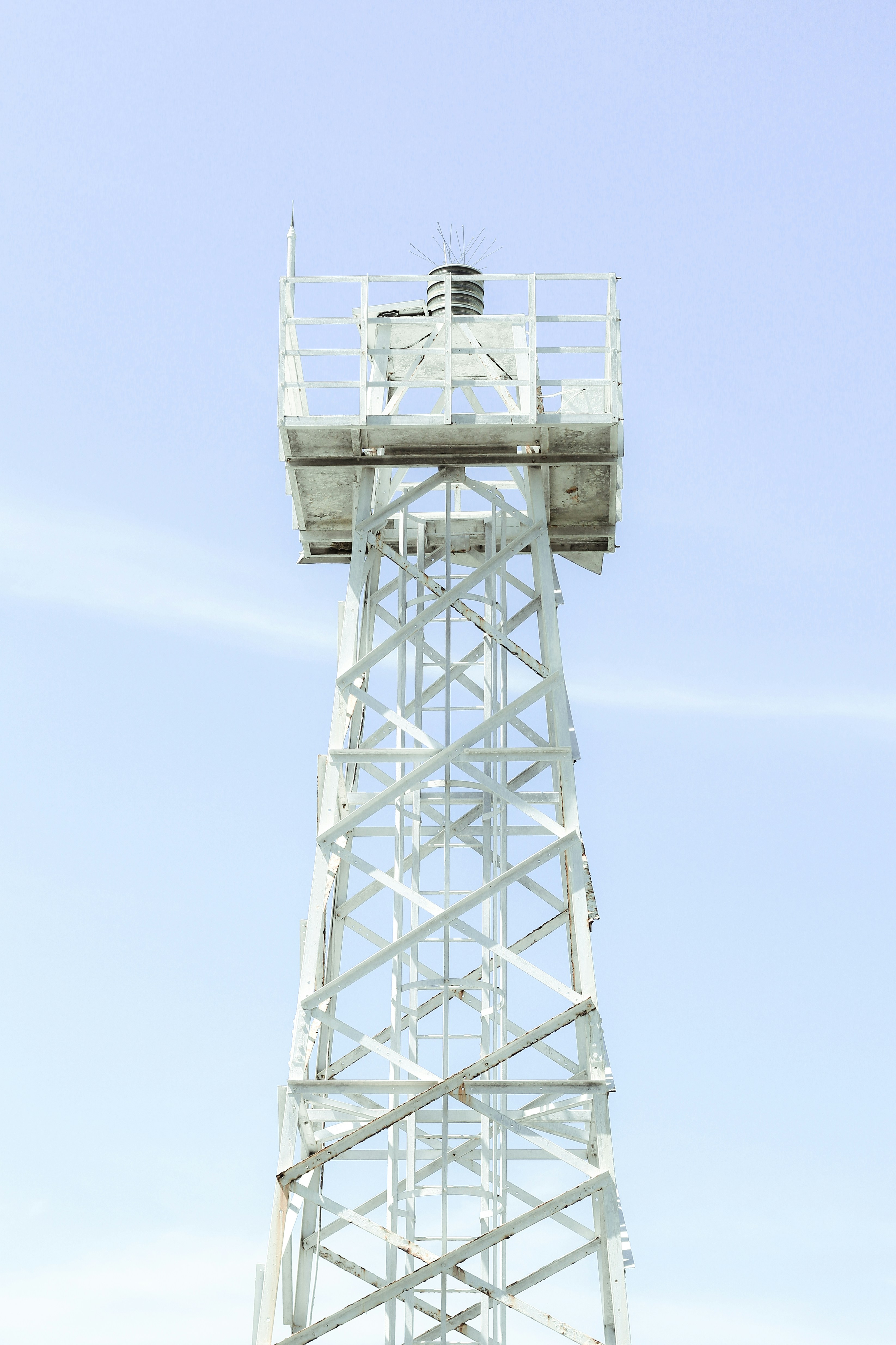 A weathered watchtower stands against a clear blue sky, its structure revealing the passage of time and elements.
