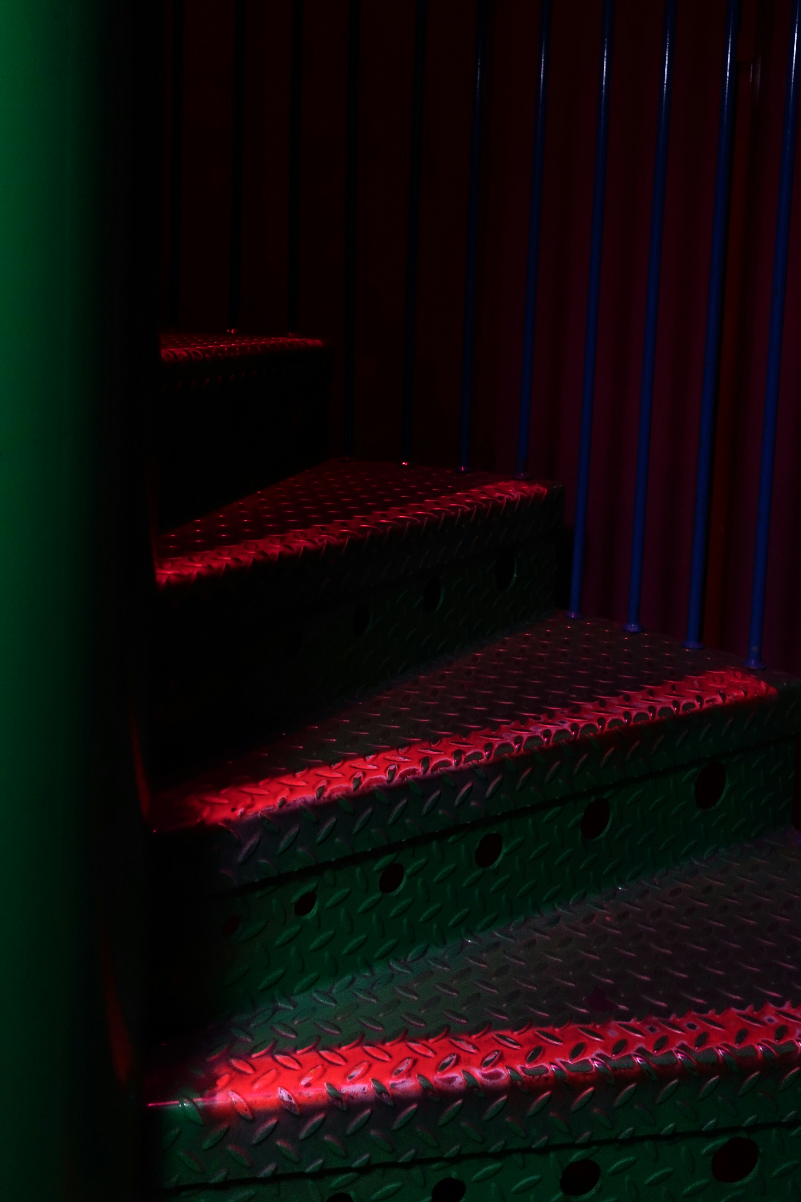 Dimly lit metal stairs with red light accents creating a dramatic contrast.