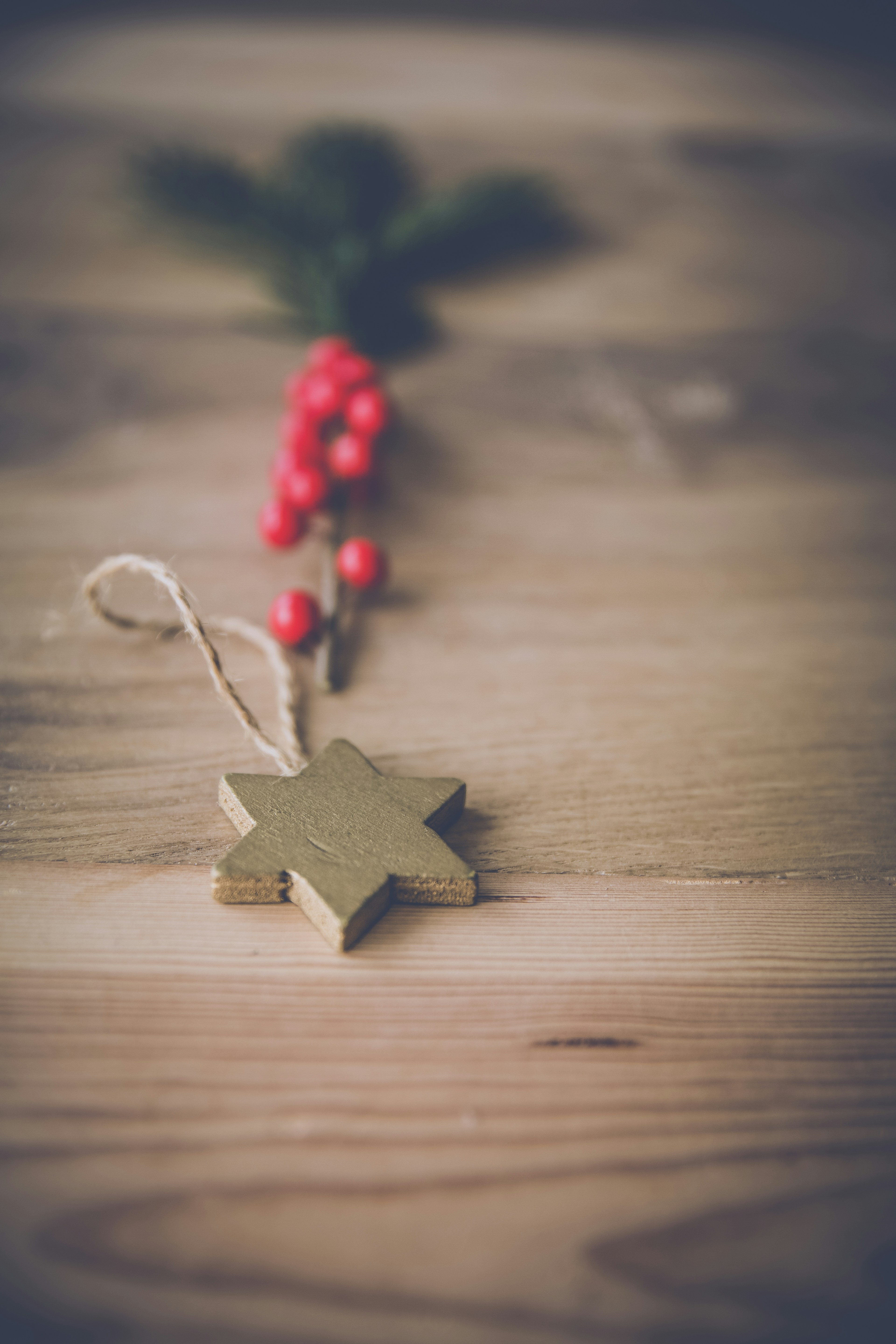 A gentle holiday ornament rests on a wooden surface with red berries trailing behind