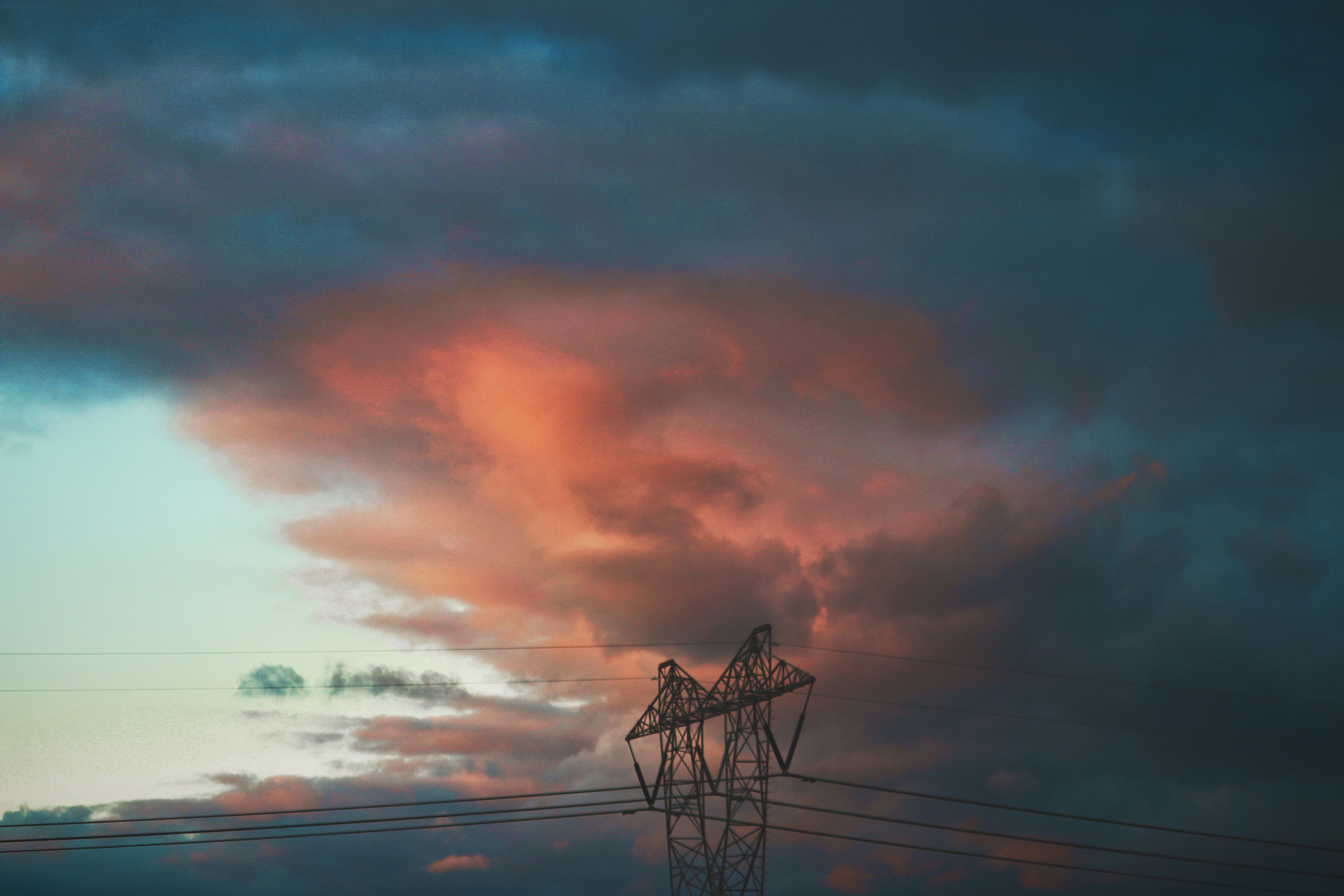 Twilight Lattice: a lone transmission tower against crimson clouds
