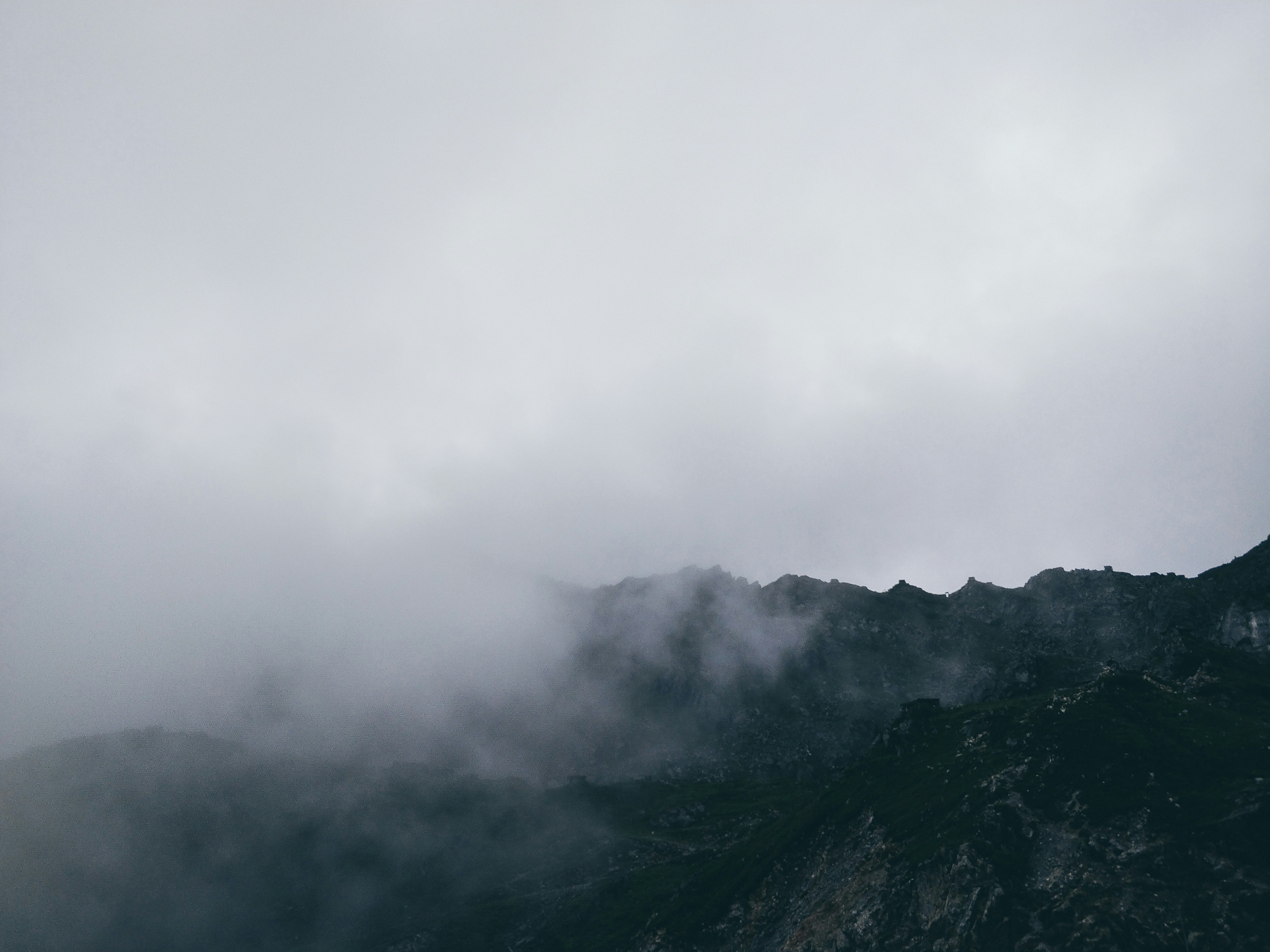 A mountain in the clouds | mountain under cloudy sky