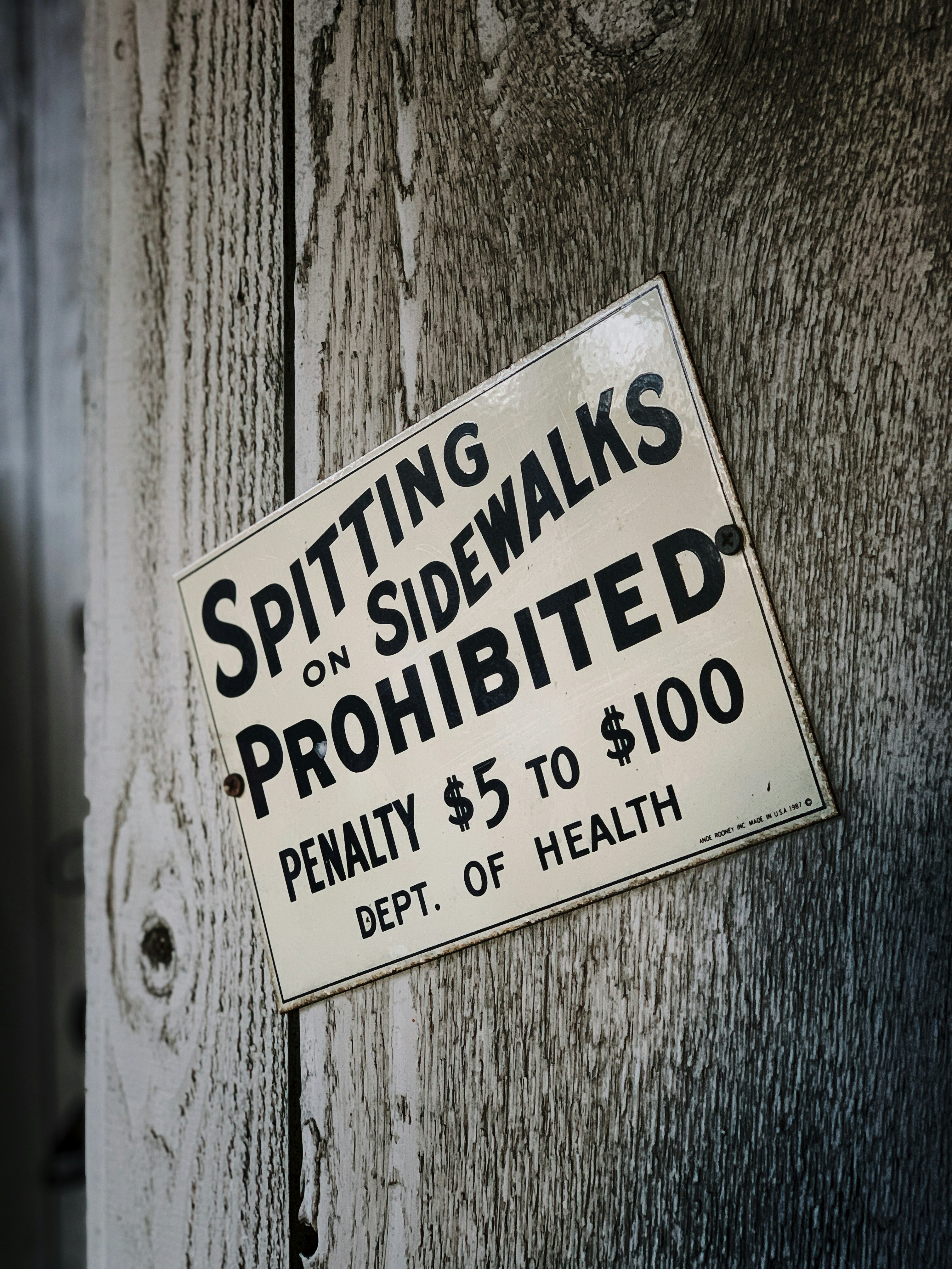 Tilted Prohibition Sign on Weathered Wood: Spiting Prohibited