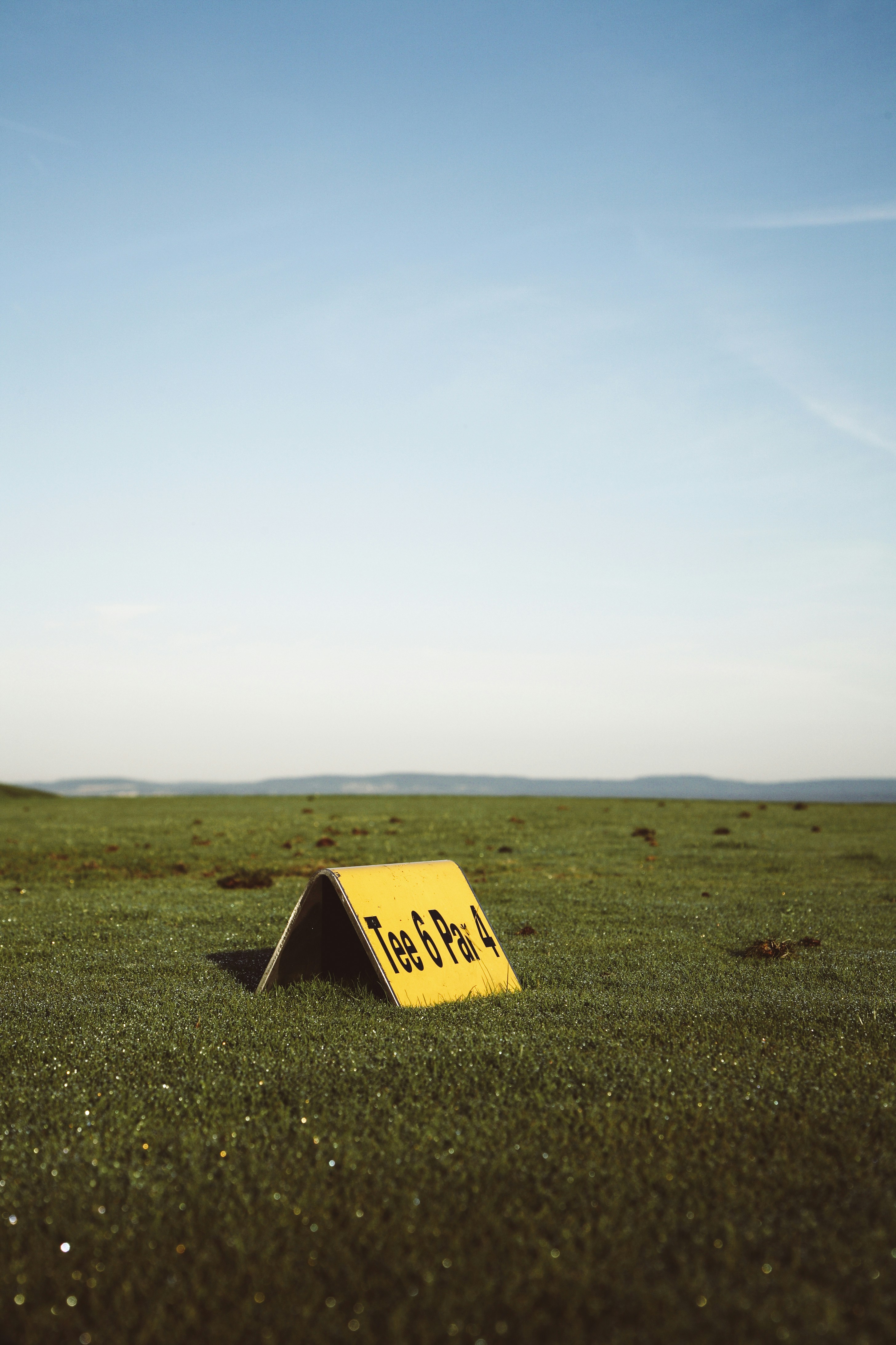 Low Yellow Sign in a Vast Grass Field Beneath a Wide Sky