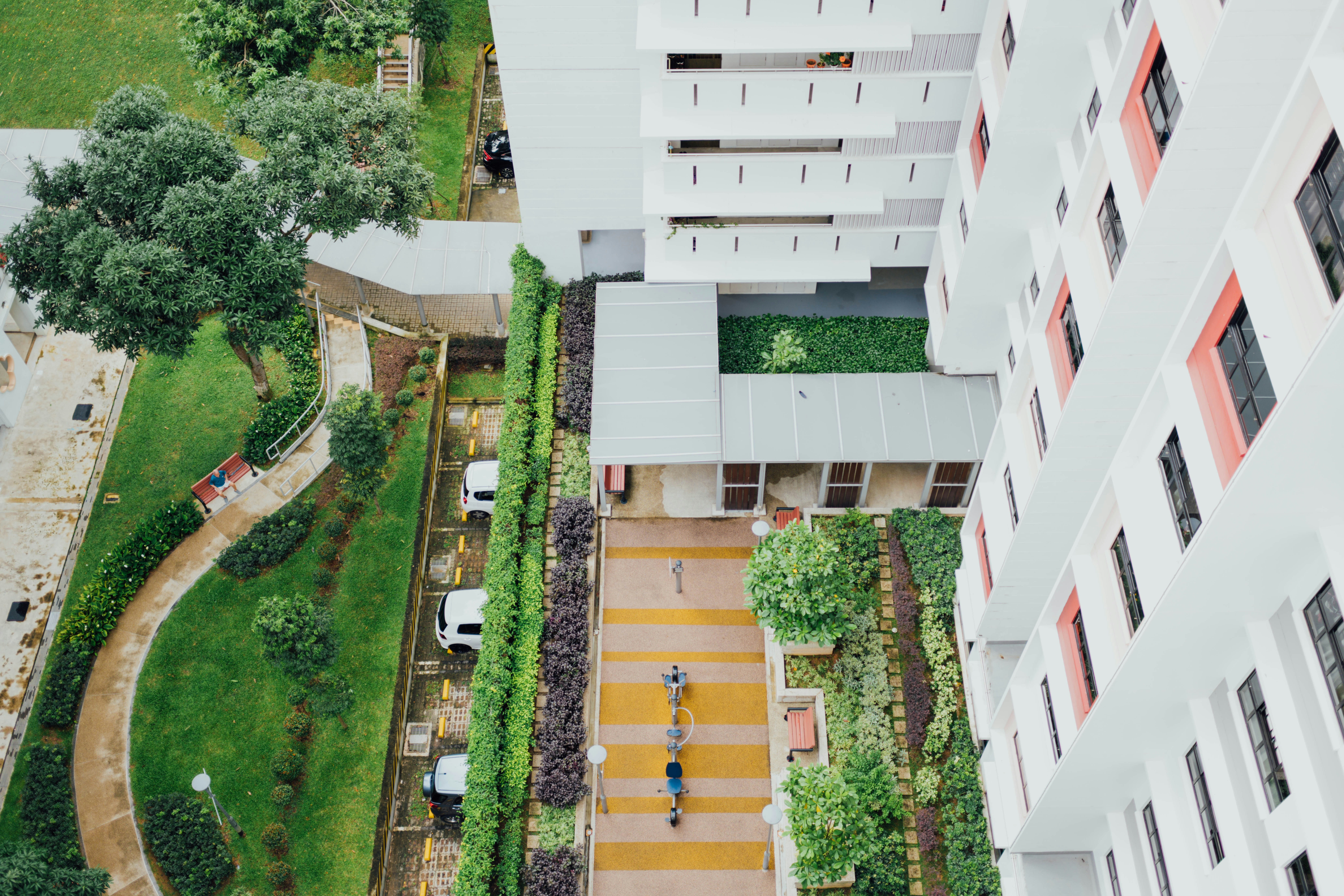 Aerial view of a building courtyard with vibrant greenery and parked cars.