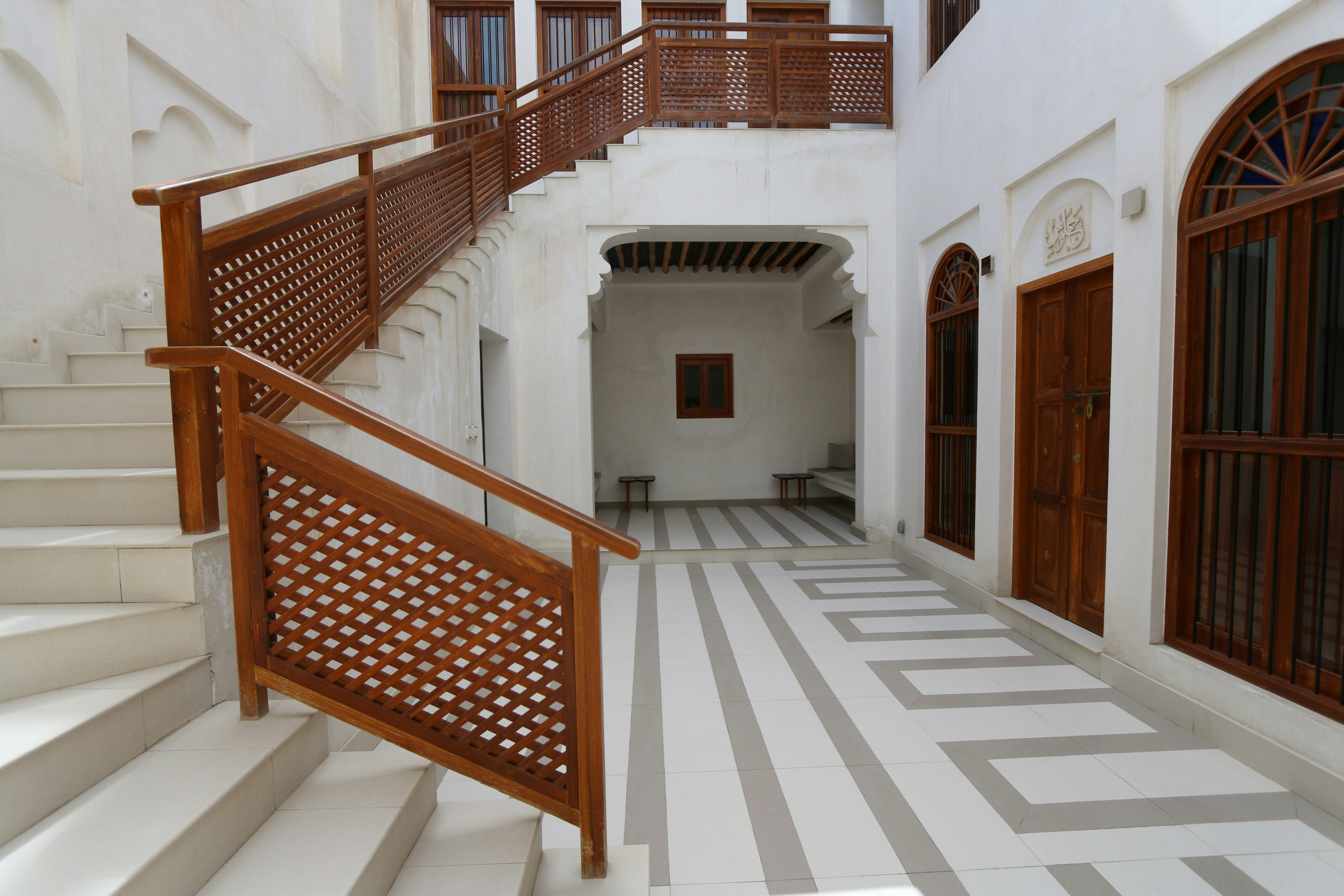 Intricately designed courtyard featuring wooden railings and patterned flooring, showcasing a blend of traditional architecture and modern aesthetics.