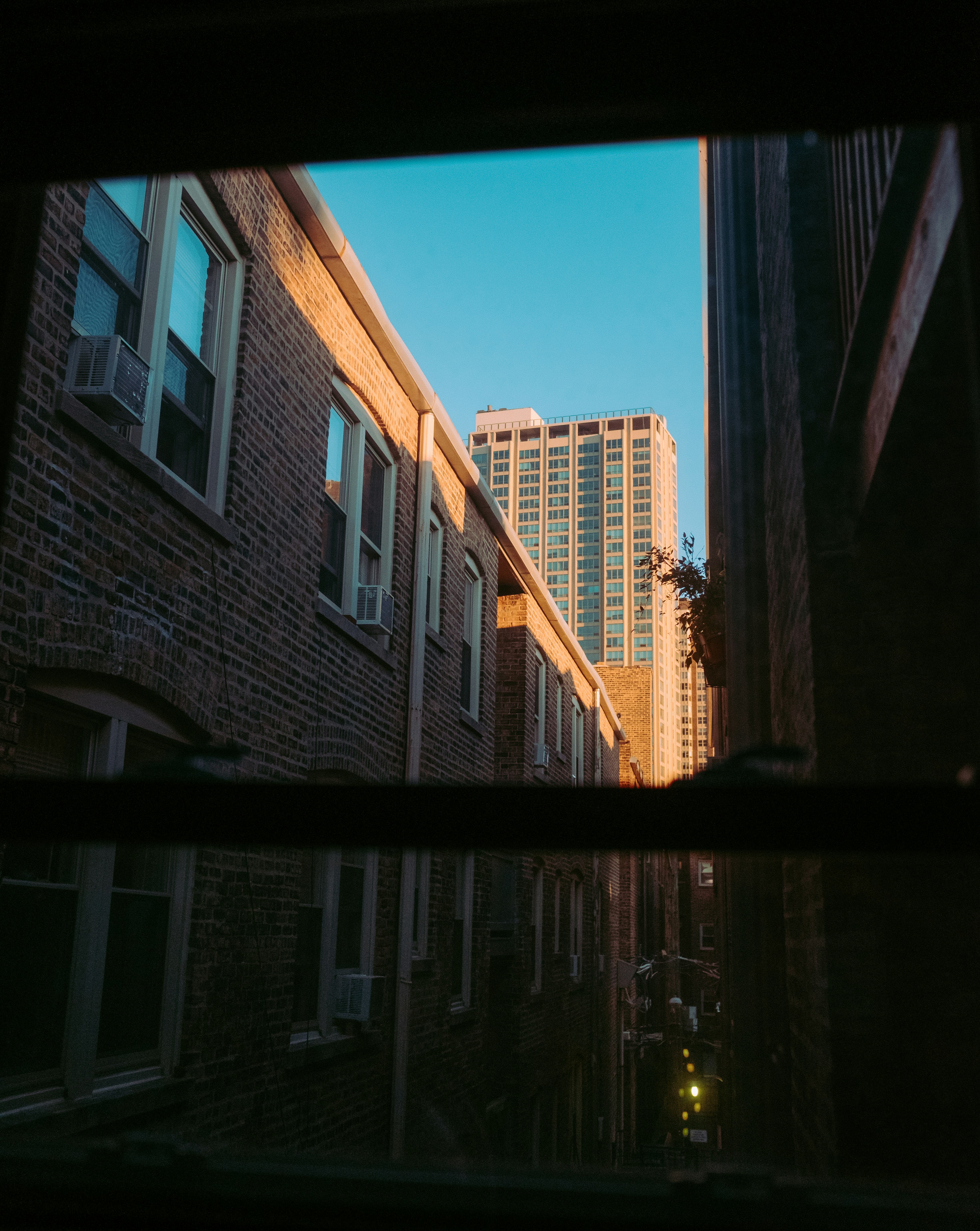 Framed Ascent: Skyward Tower Piercing a Brick Alley