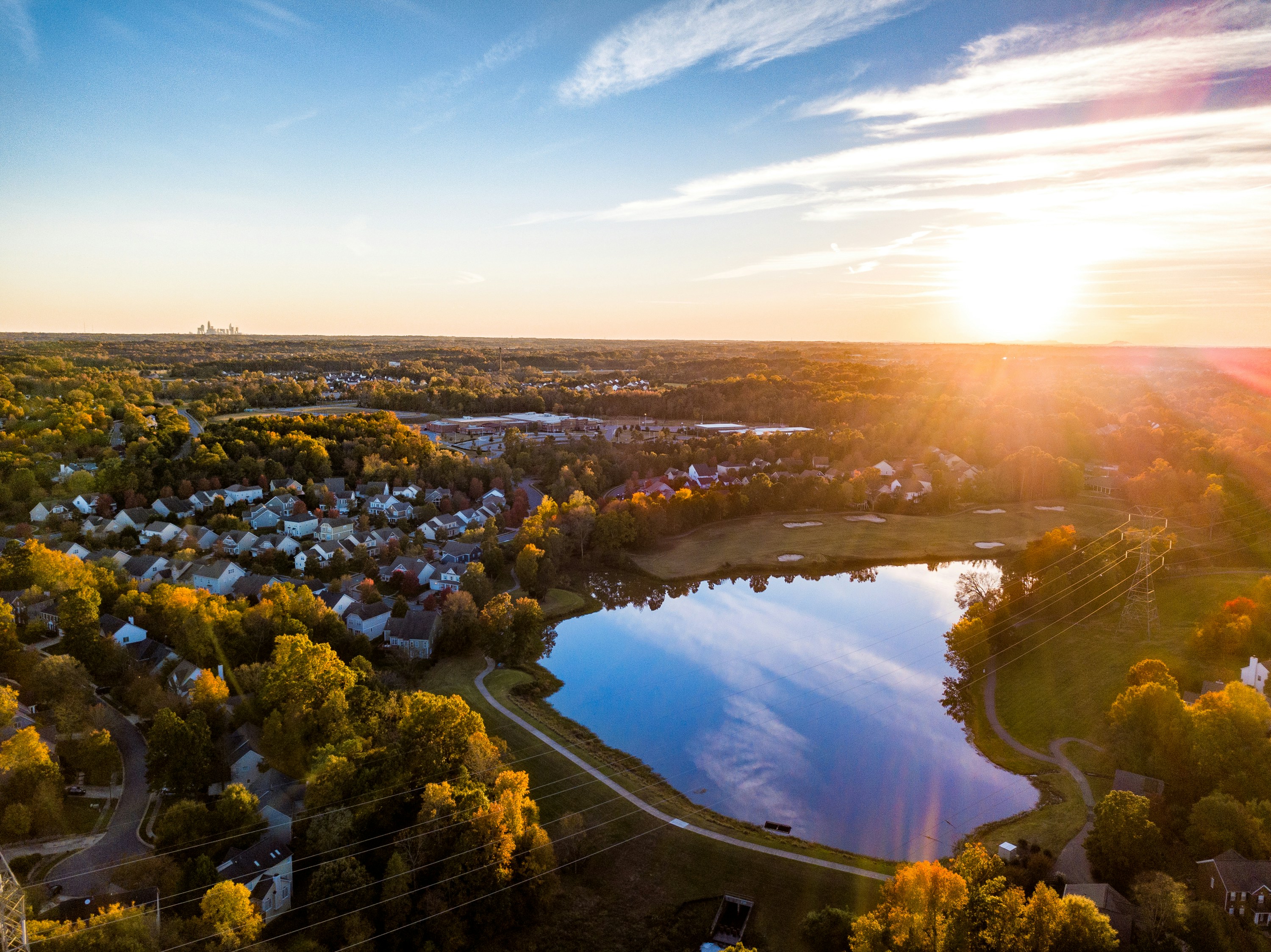 I took this photo of our neighborhood pond the day after hurricane Michael passed through Charlotte. We had just shy of 24 hours of rainfall and were luck to go through it unscathed. This photo symbolizes the dawn of a new day after the hurricane. The dawn of new chances and opportunity. | houses near lake surrounded with trees