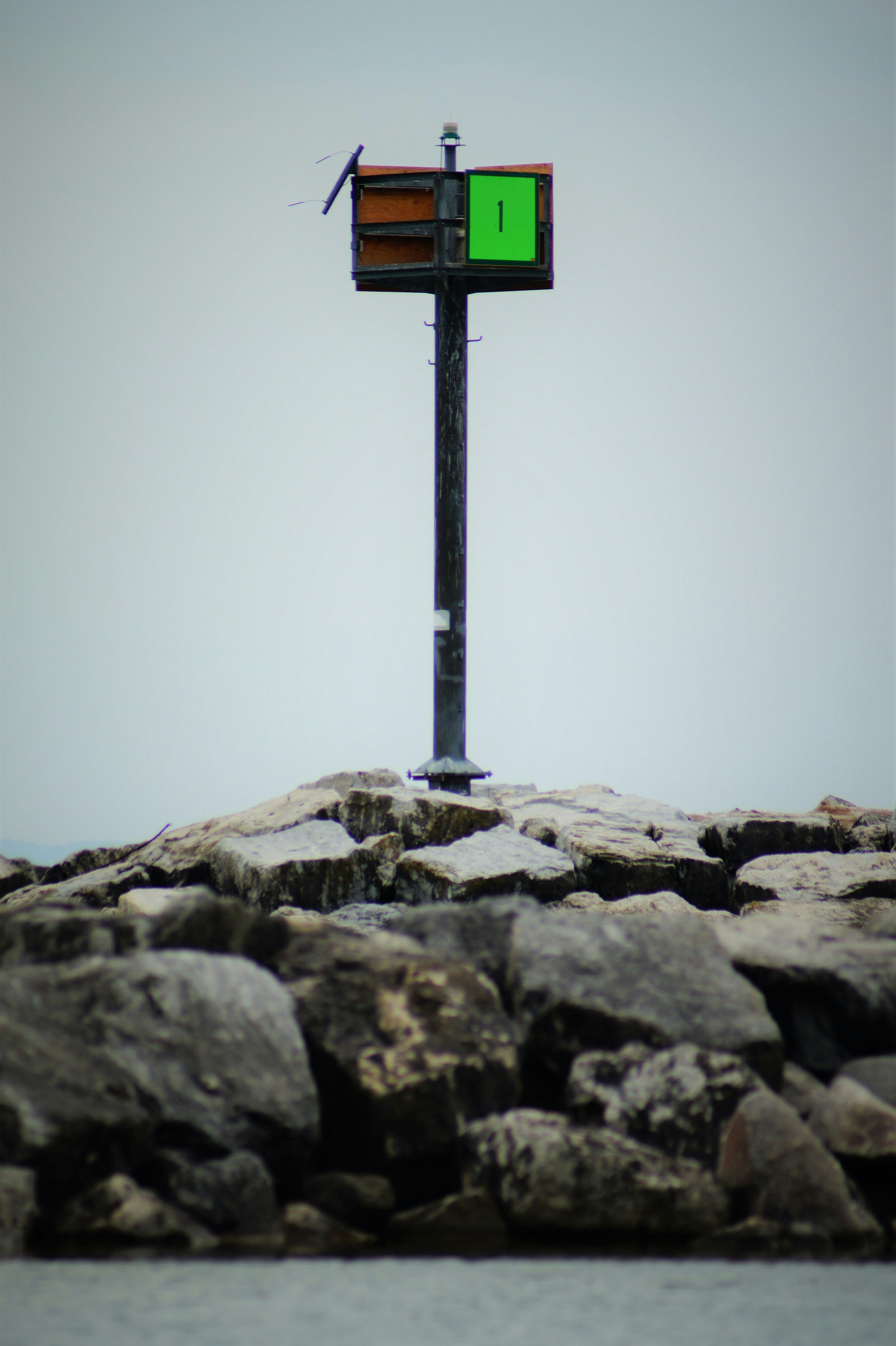 Green Marker Sentinel: A Lone Beacon on a Rocky Breakwater