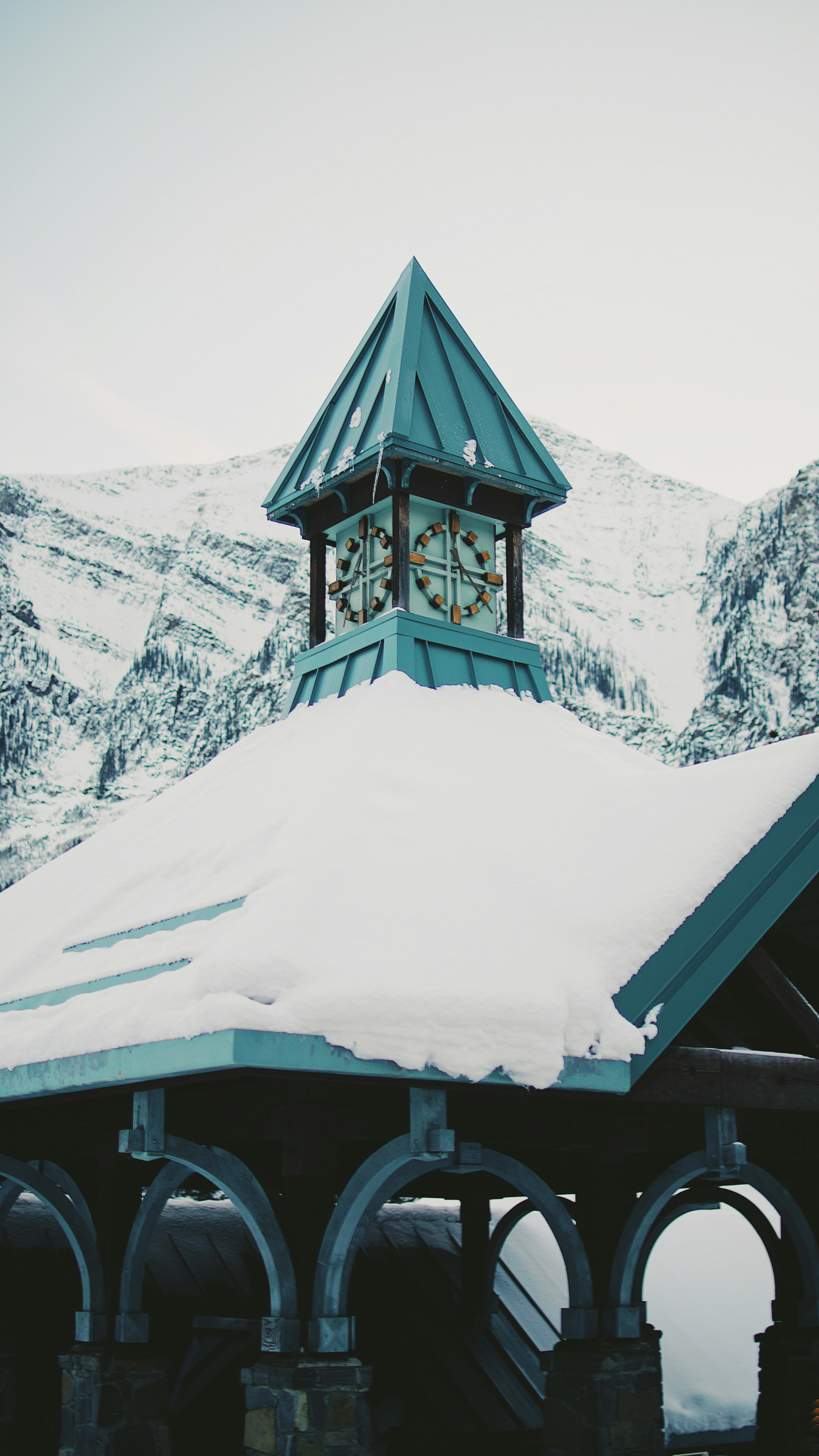 Teal Clock Tower Rising Above a Snow-Capped Alpine Roof