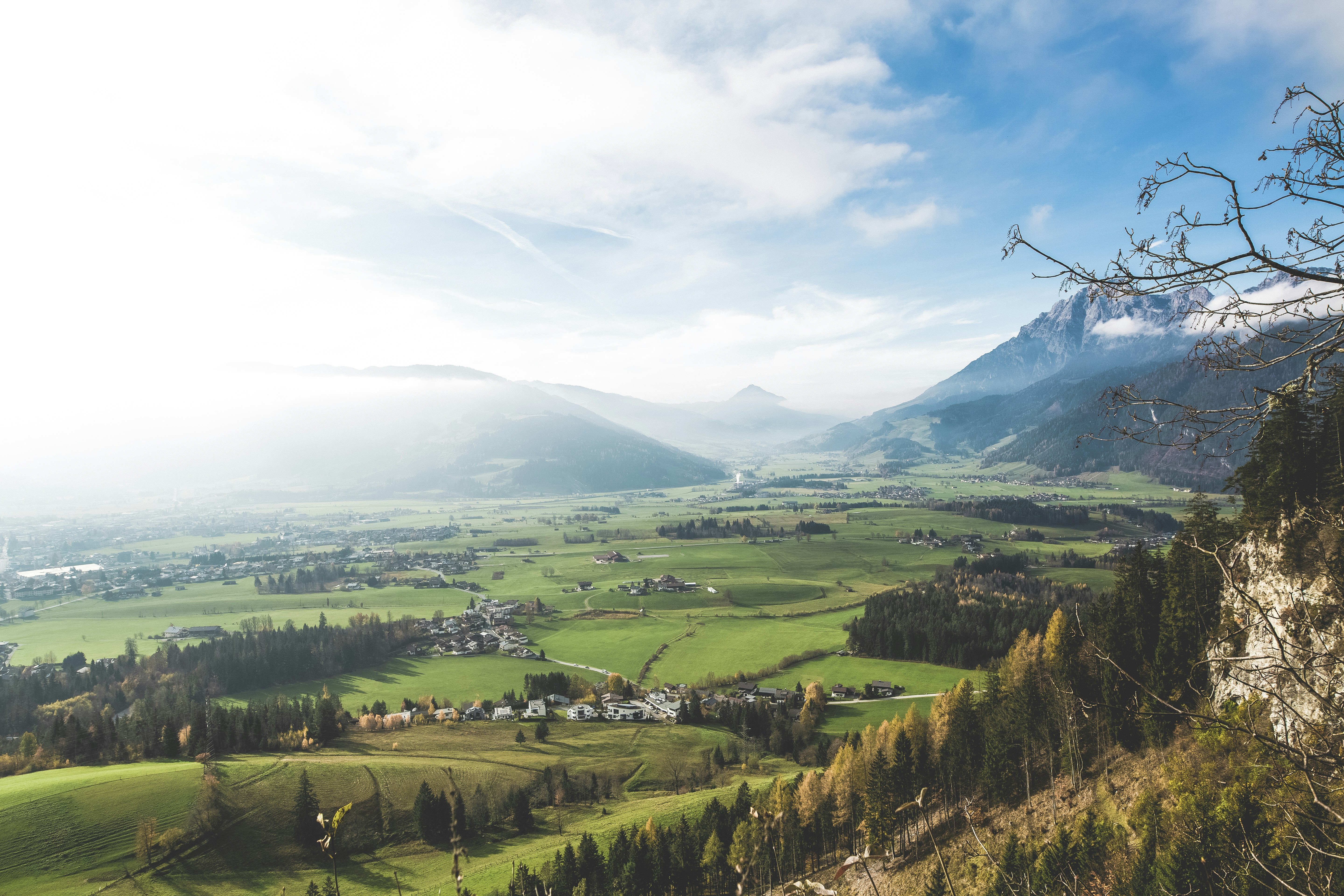 Expansive view of lush green valleys bordered by distant mountains under a partly cloudy sky.