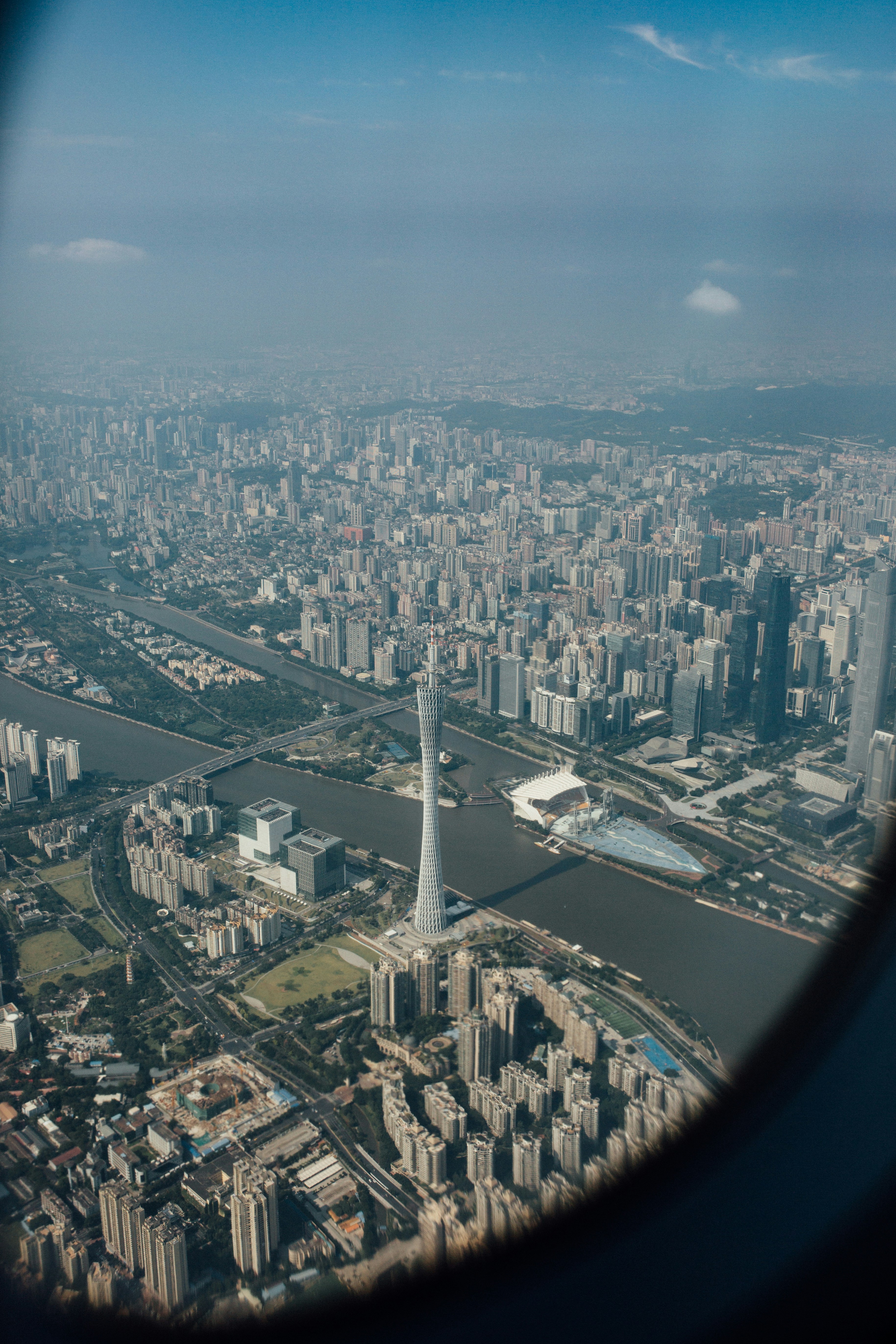Aerial perspective showcasing a sprawling cityscape with a prominent tower amidst a network of rivers and buildings.
