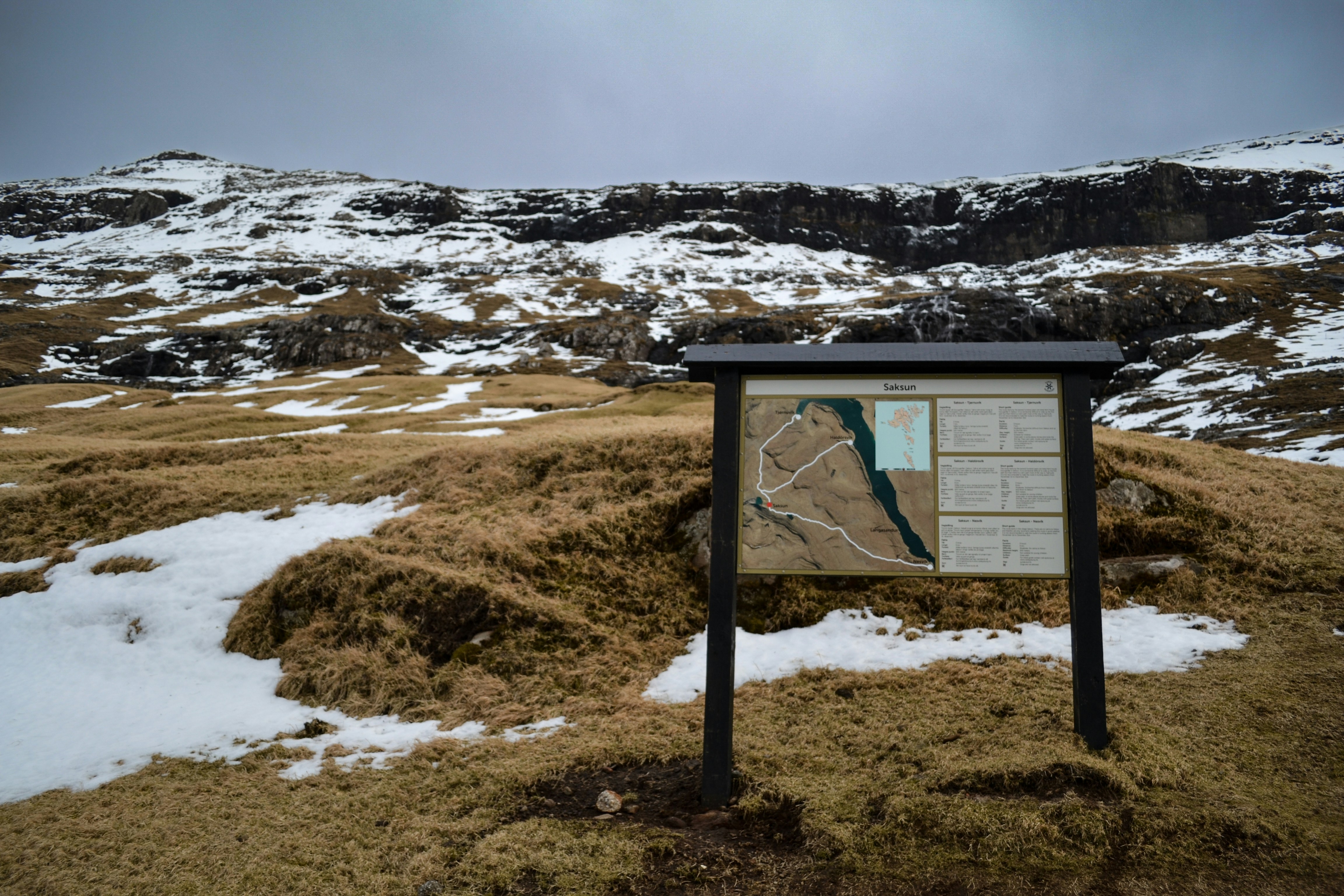 Black map guide on hill beside snow-covered hill photo – Free Saksun ...