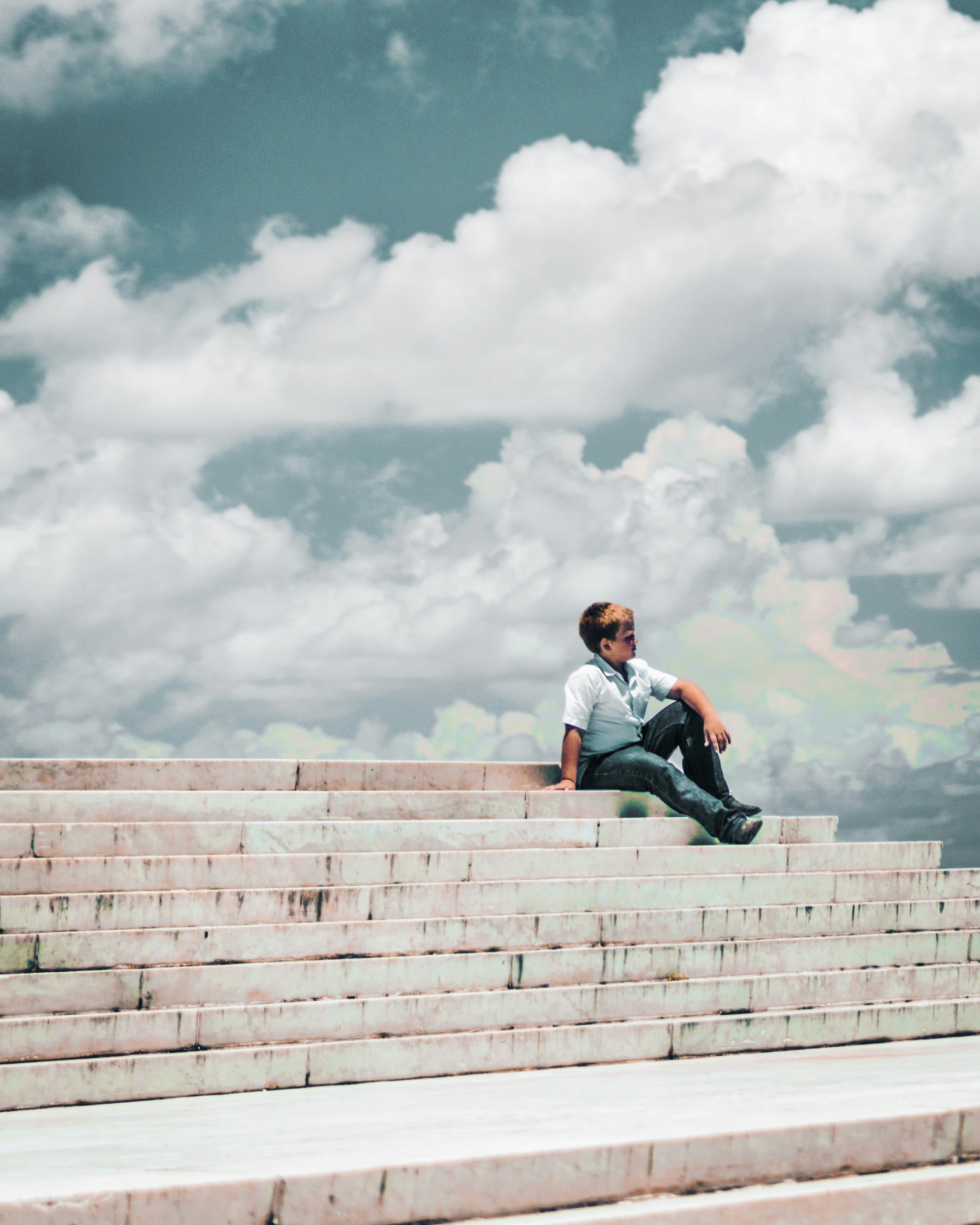 Lone Dreamer on Concrete Steps Under a Vast Cloudscape