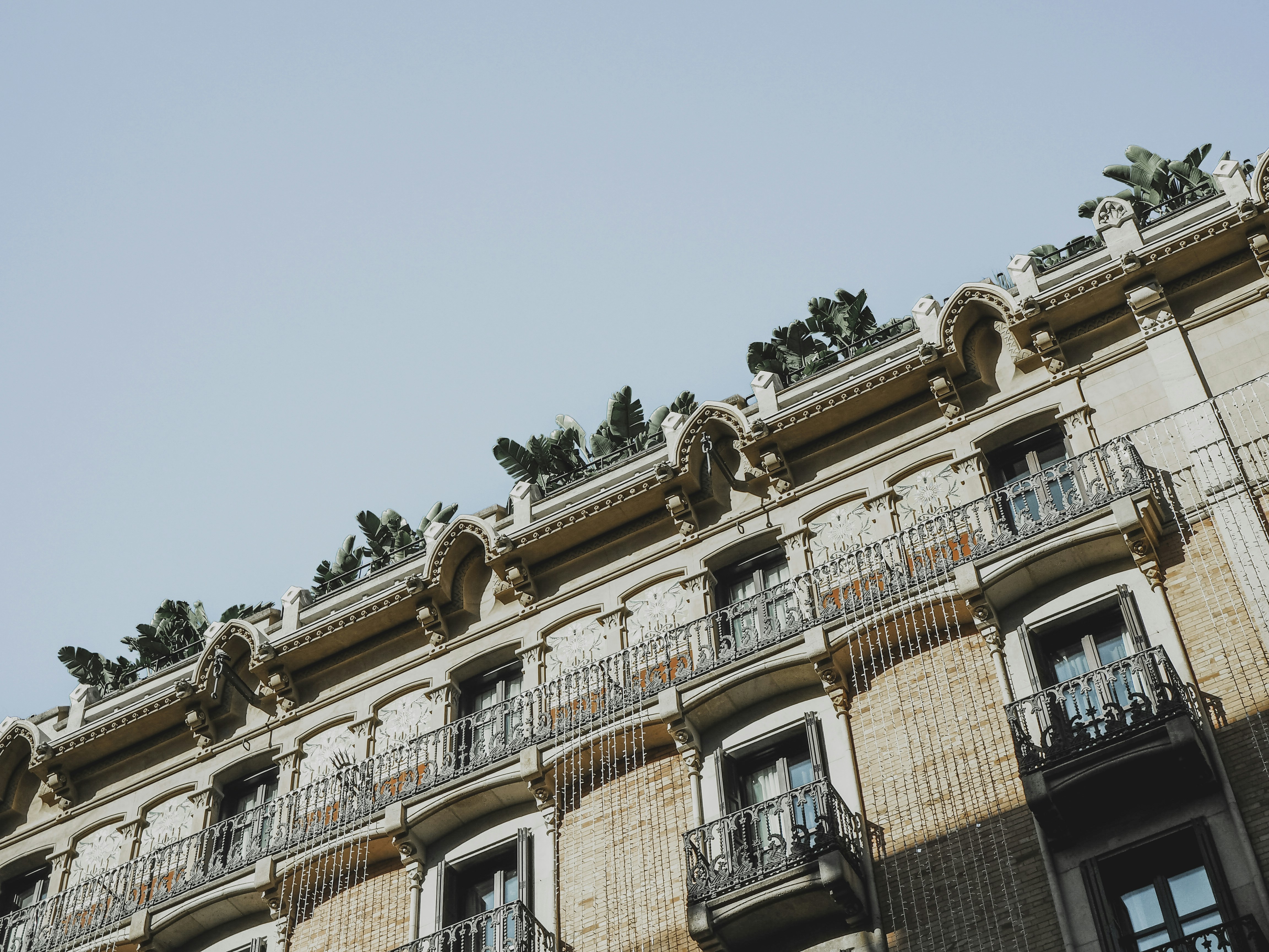 Intricate balconies and lush greenery adorn the historic building against a clear sky.