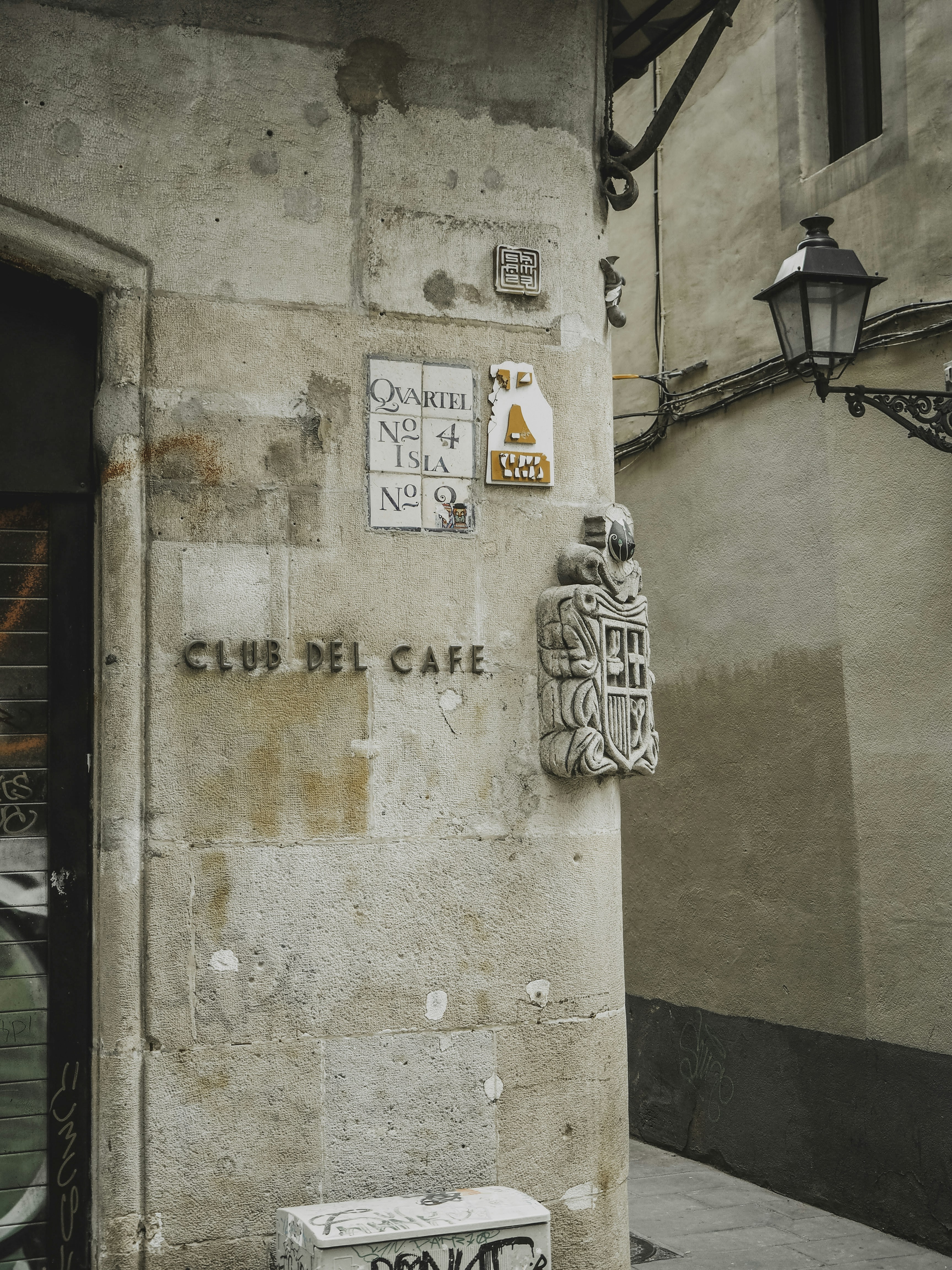 Weathered stone wall featuring the sign 'CLUB DEL CAFE' and various street art elements, capturing the essence of urban life.