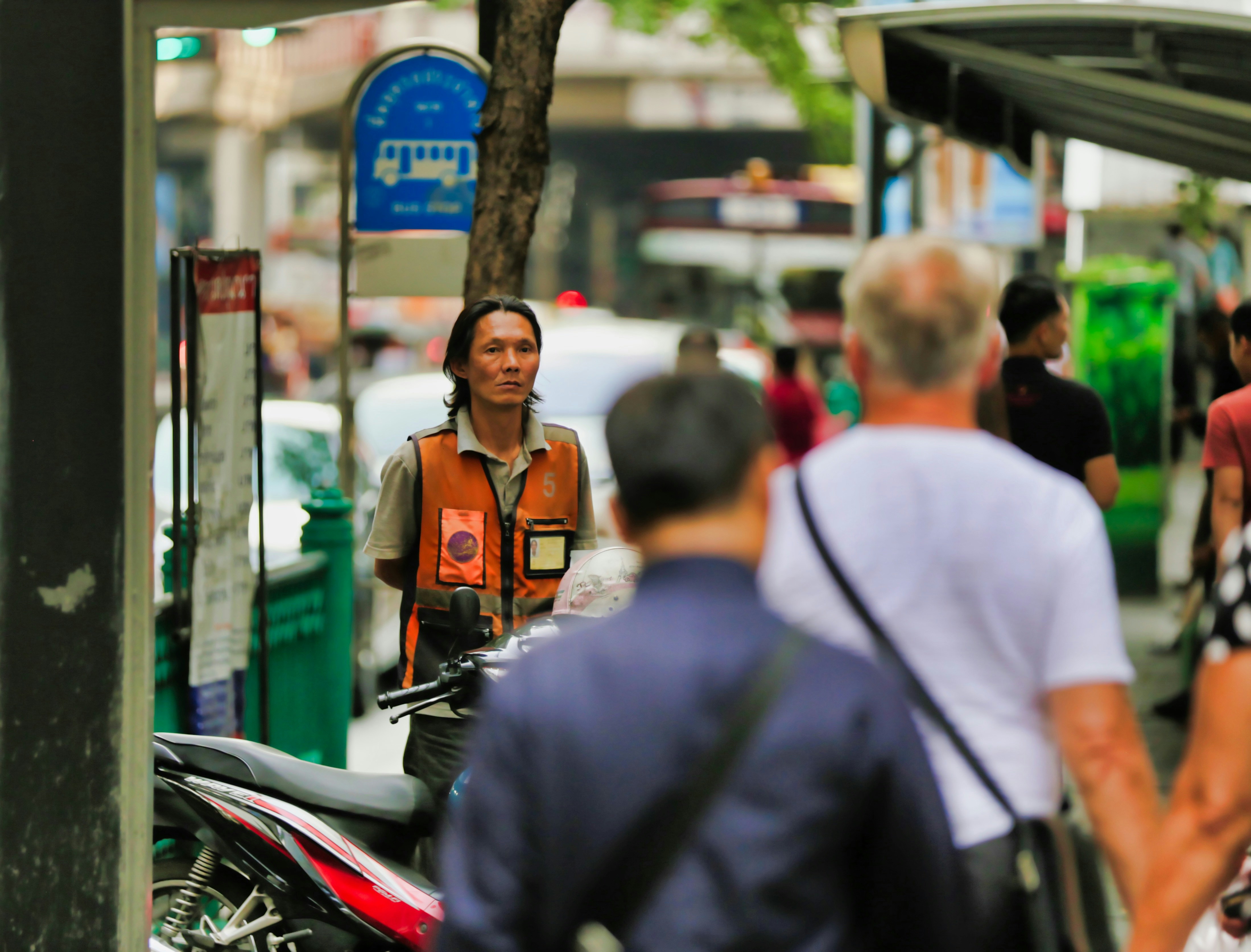 people walking beside man in orange vest