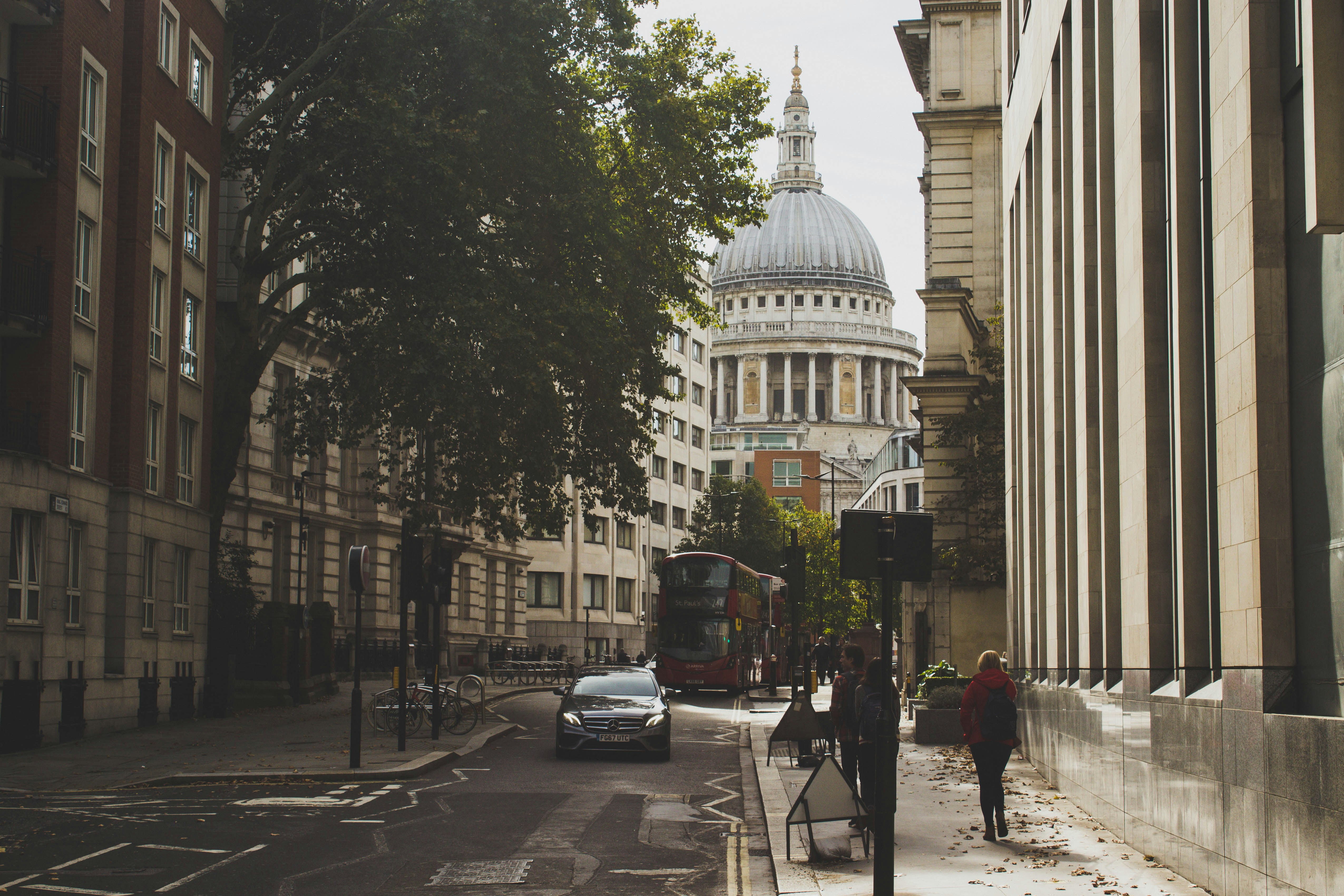 St. Paul's Cathedral dome framed by city buildings under a cloudy sky.