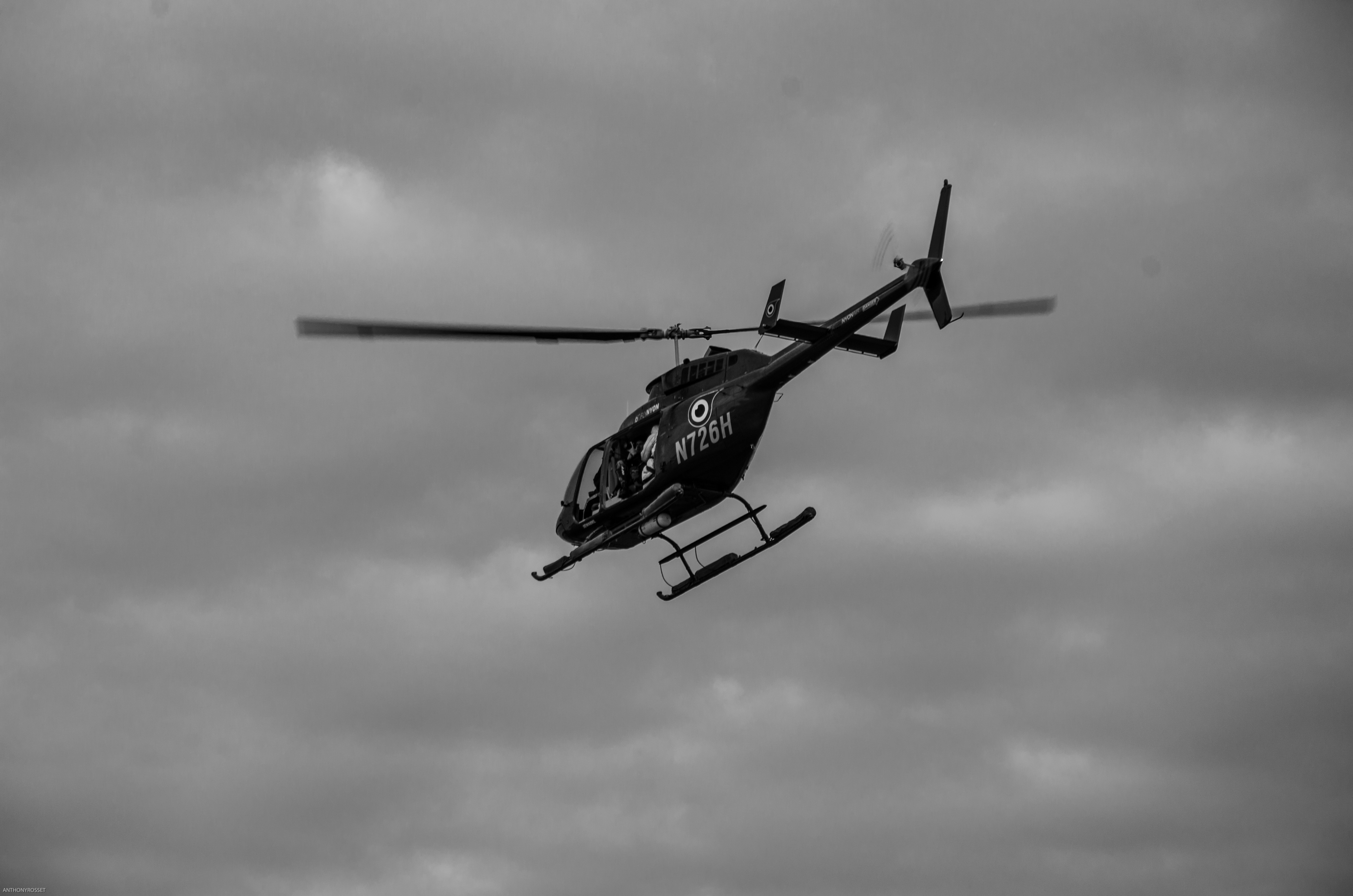 Grayscale Hover: A helicopter carving through a clouded horizon