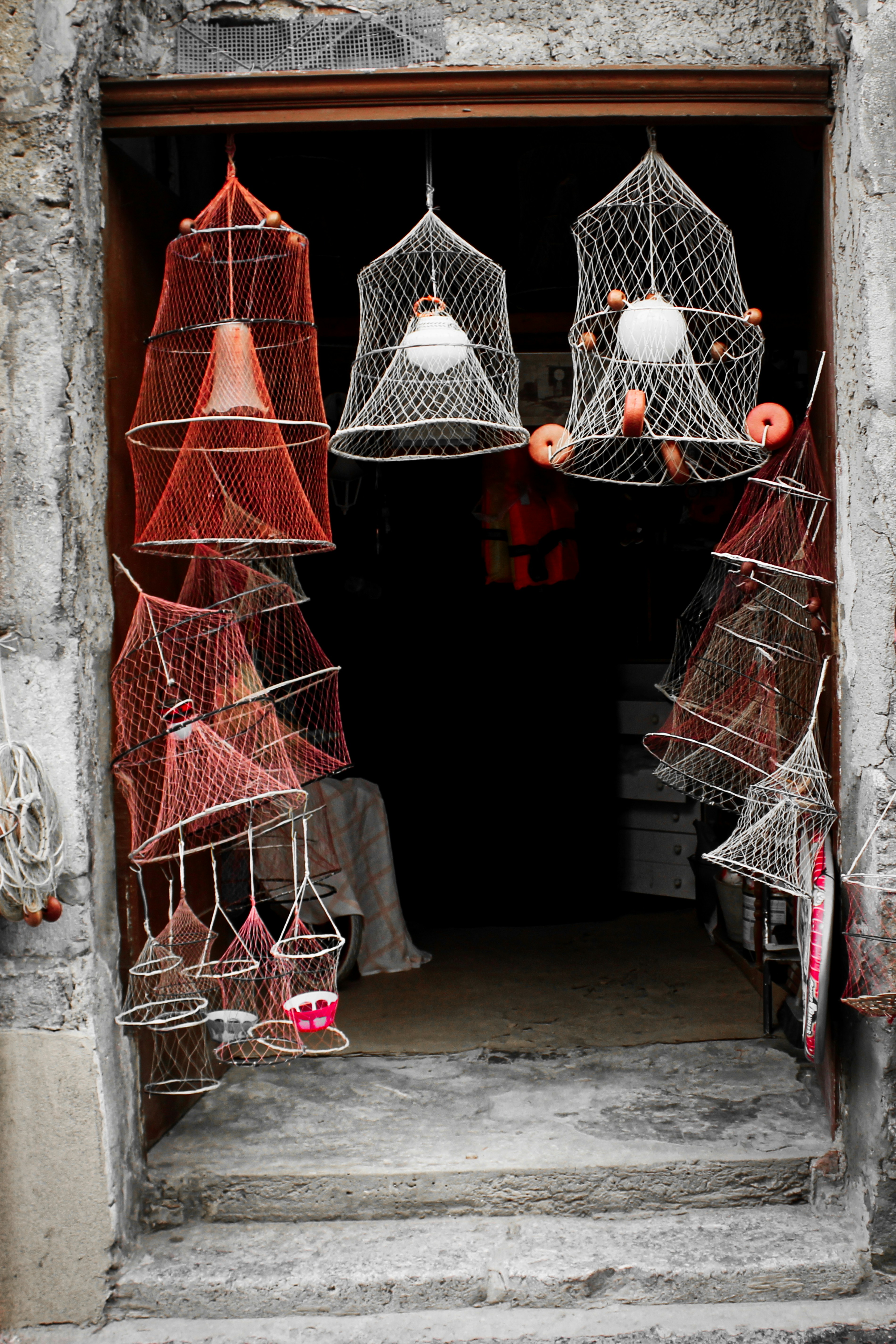 Threshold of Nets: Red and White Cages Framing a Dim Stone Doorway