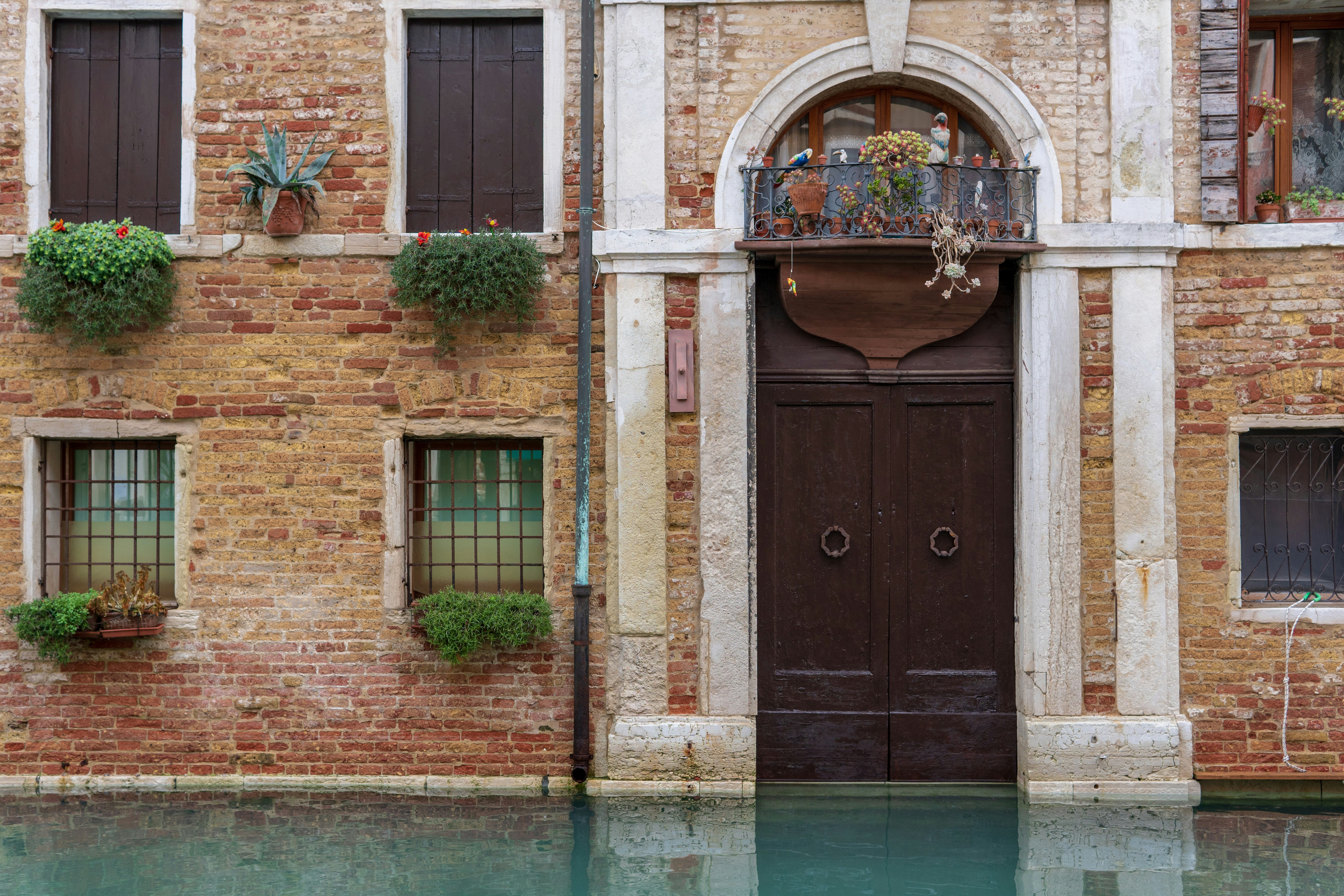 Doorway Over Water: A Brick-Faced Canal Home Framed by Greenery