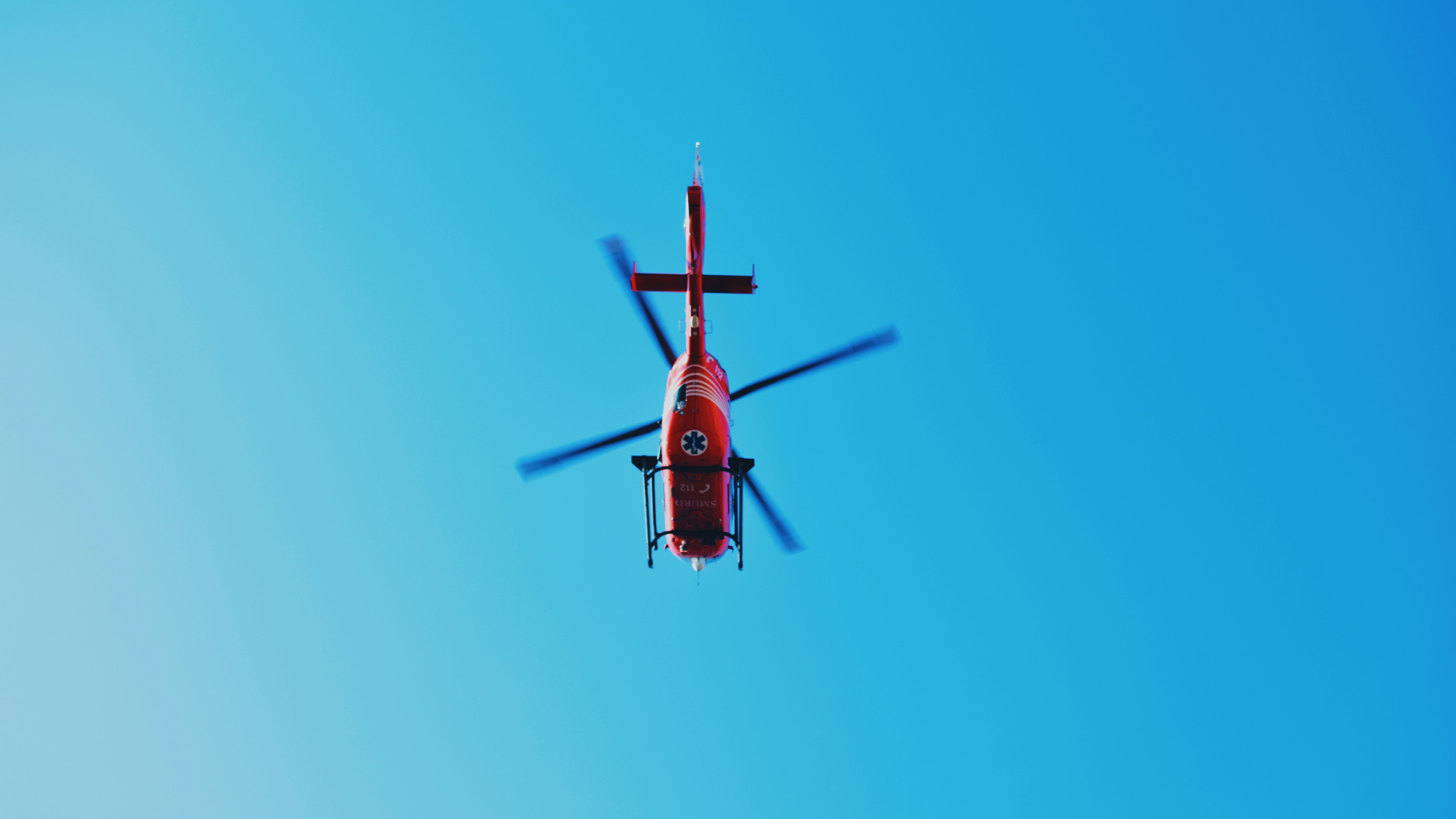 Crimson Helicopter Against Azure Skies