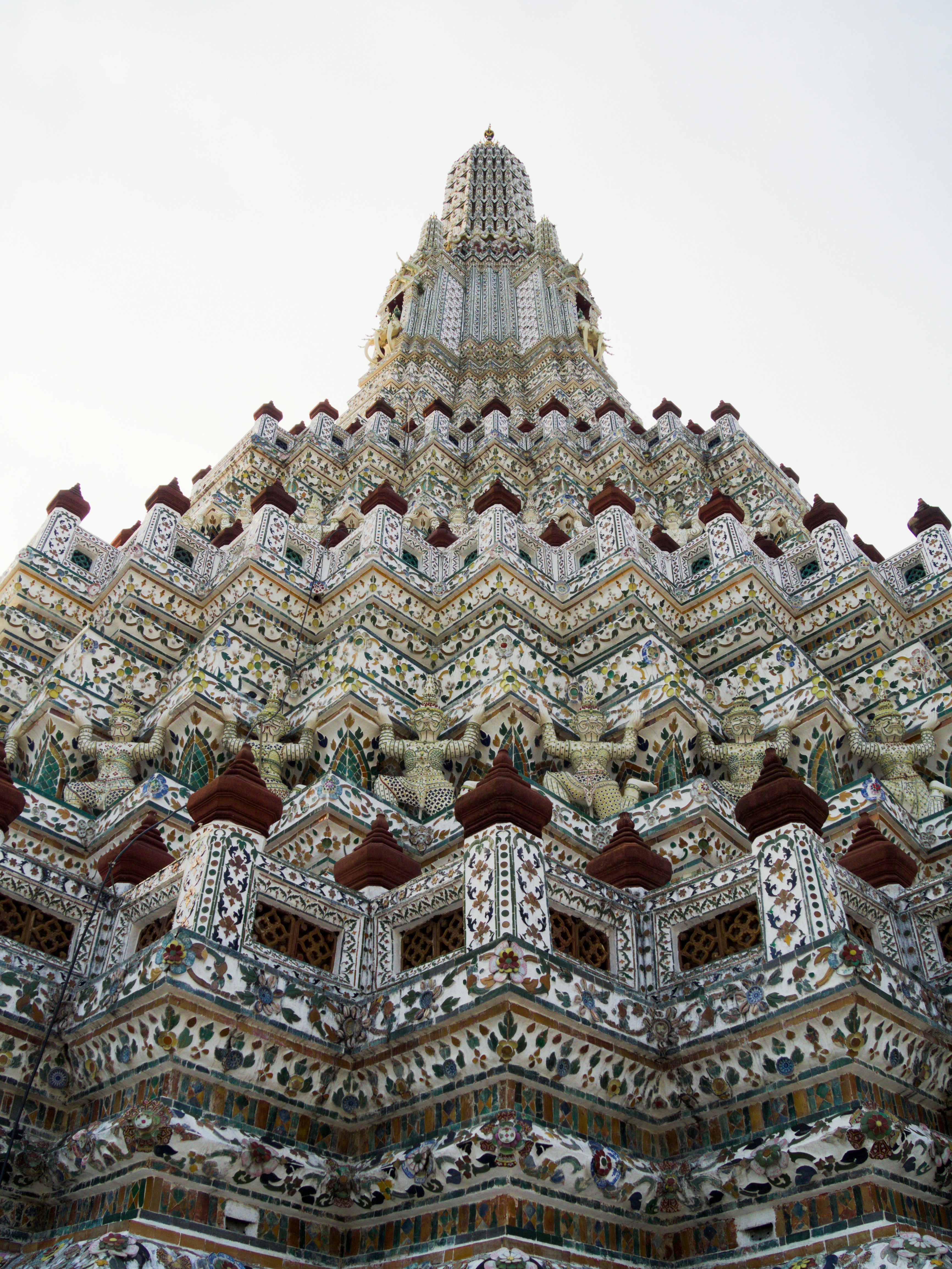 Ornate spire of Wat Arun temple in Bangkok with detailed ceramic patterns.