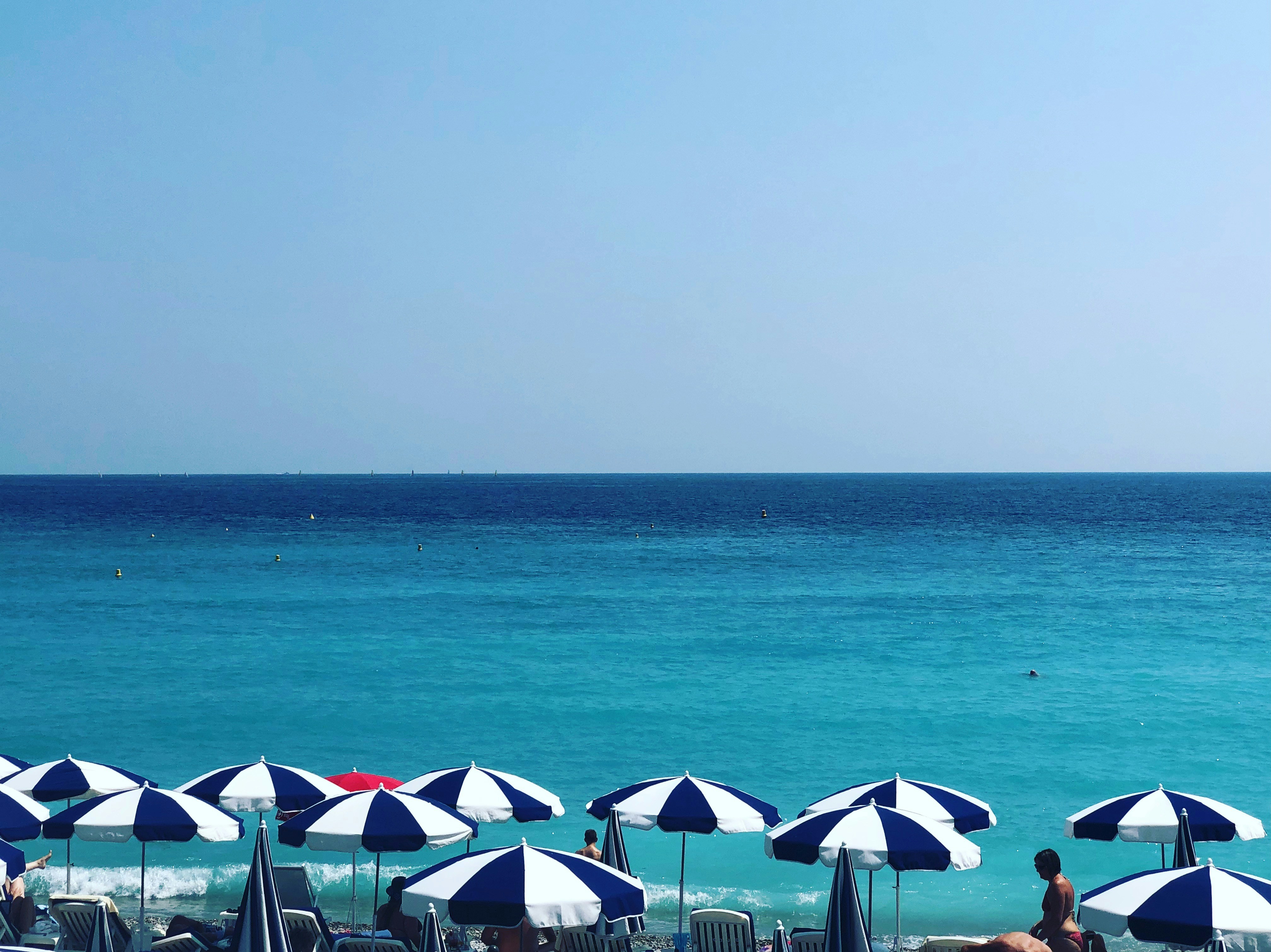 Colorful beach umbrellas line the shore against a backdrop of tranquil turquoise waters. The scene invites relaxation and leisure.