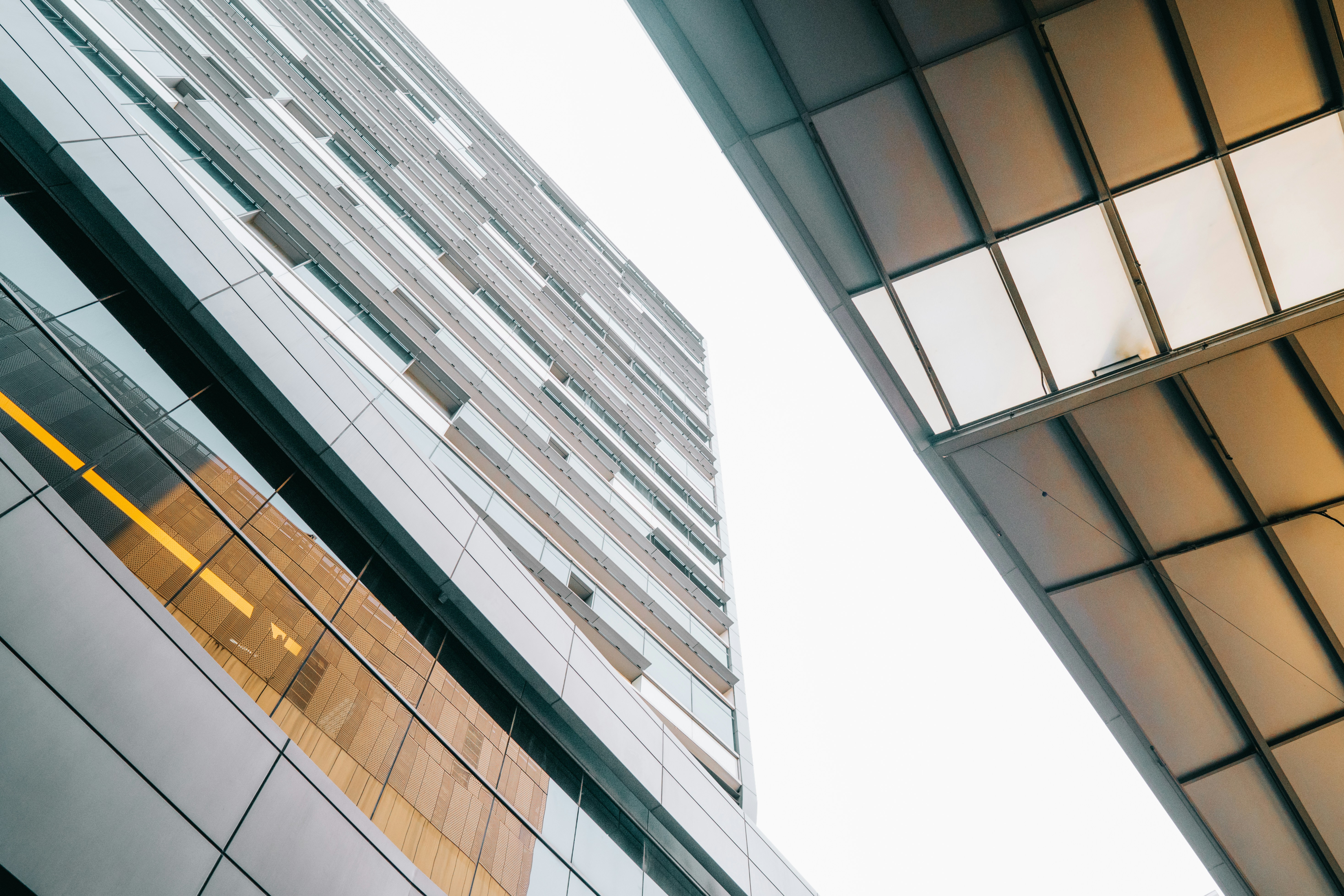 Glass and steel building facade viewed from below against a white sky.