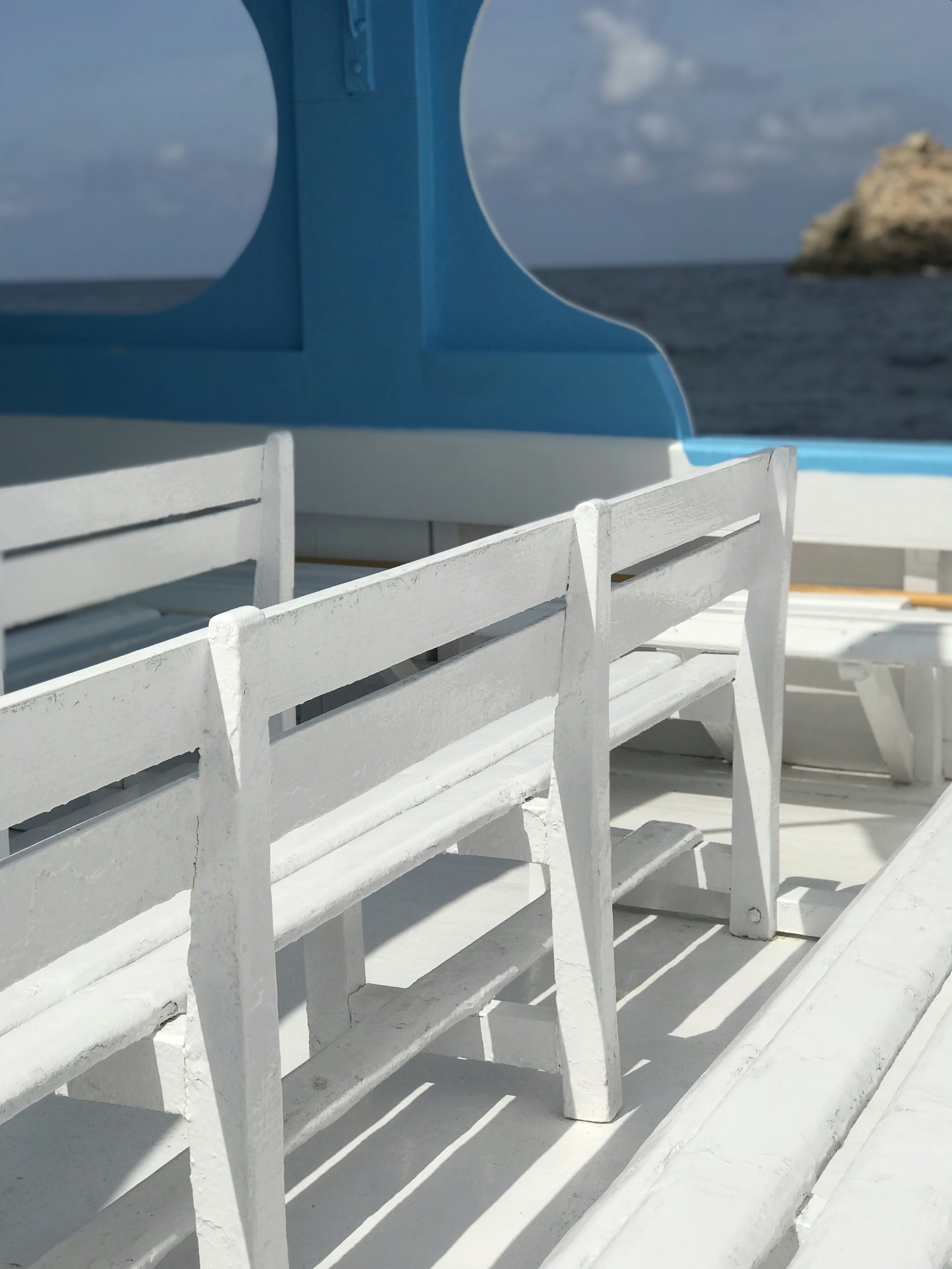 White Bench Geometry on a Blue-Hued Boat Deck by the Sea
