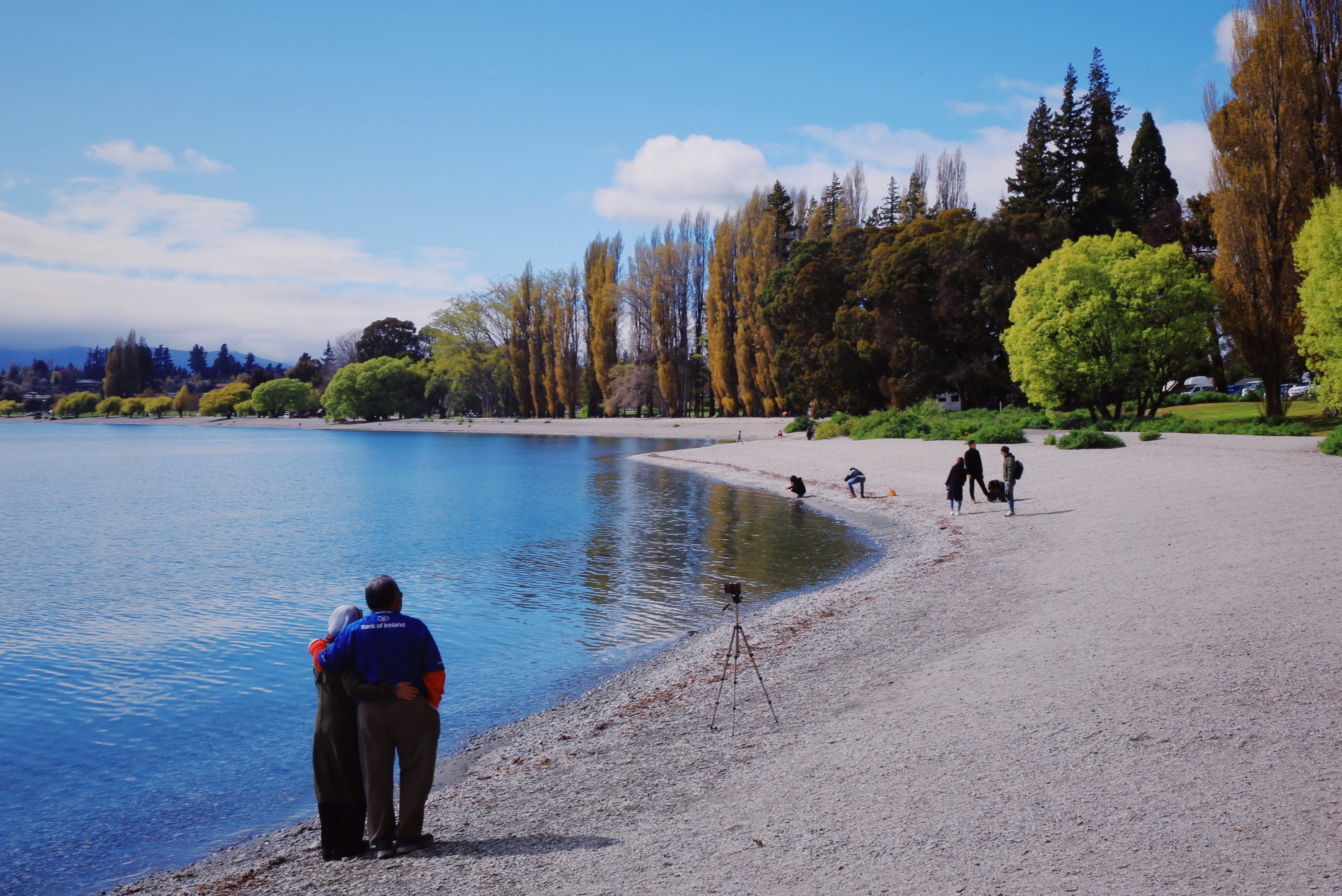 Blue-sleeved silhouette by the lakeside with a waiting tripod