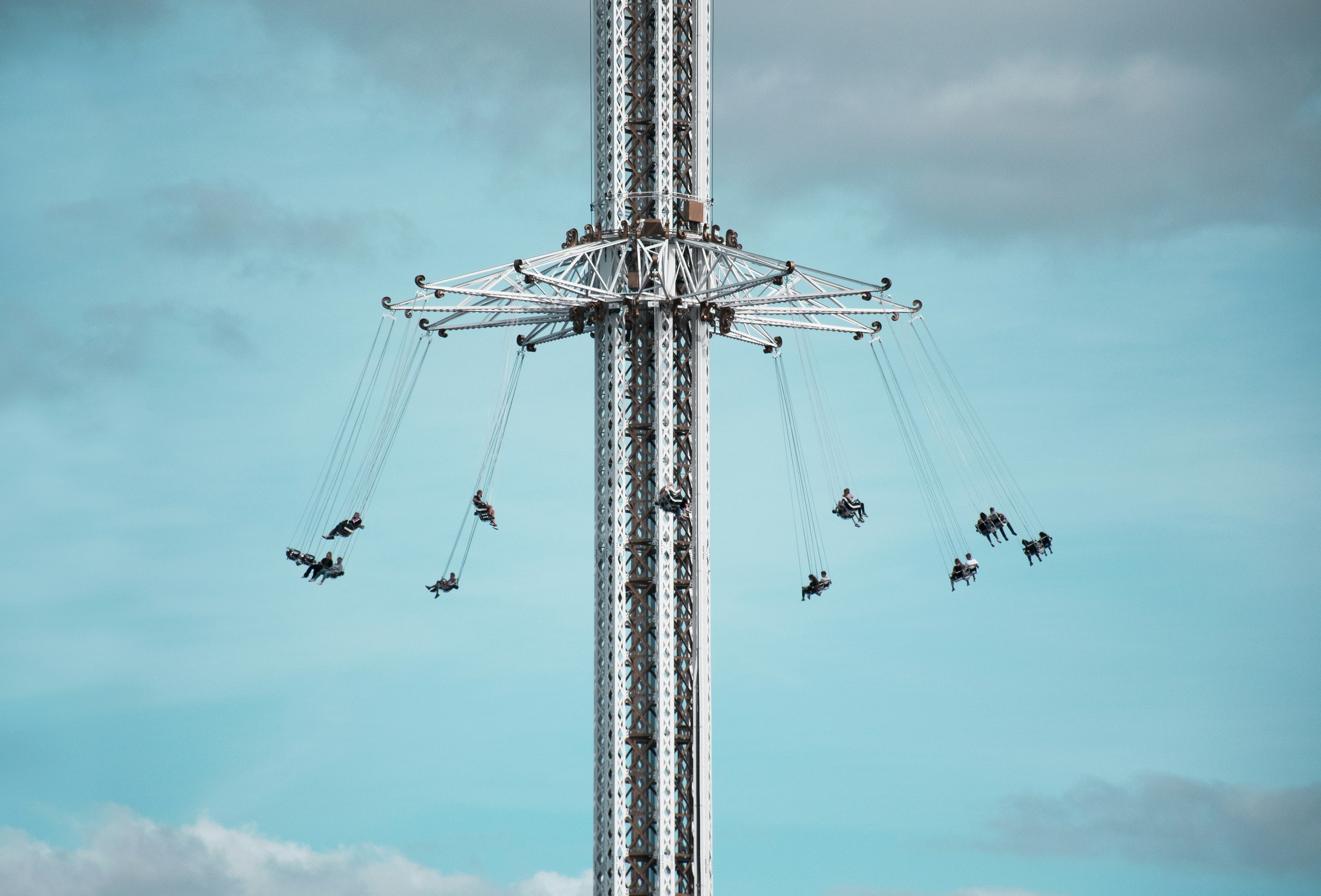 Thrilling swing ride suspended from a towering structure against a bright blue sky, showcasing the excitement of amusement park attractions.