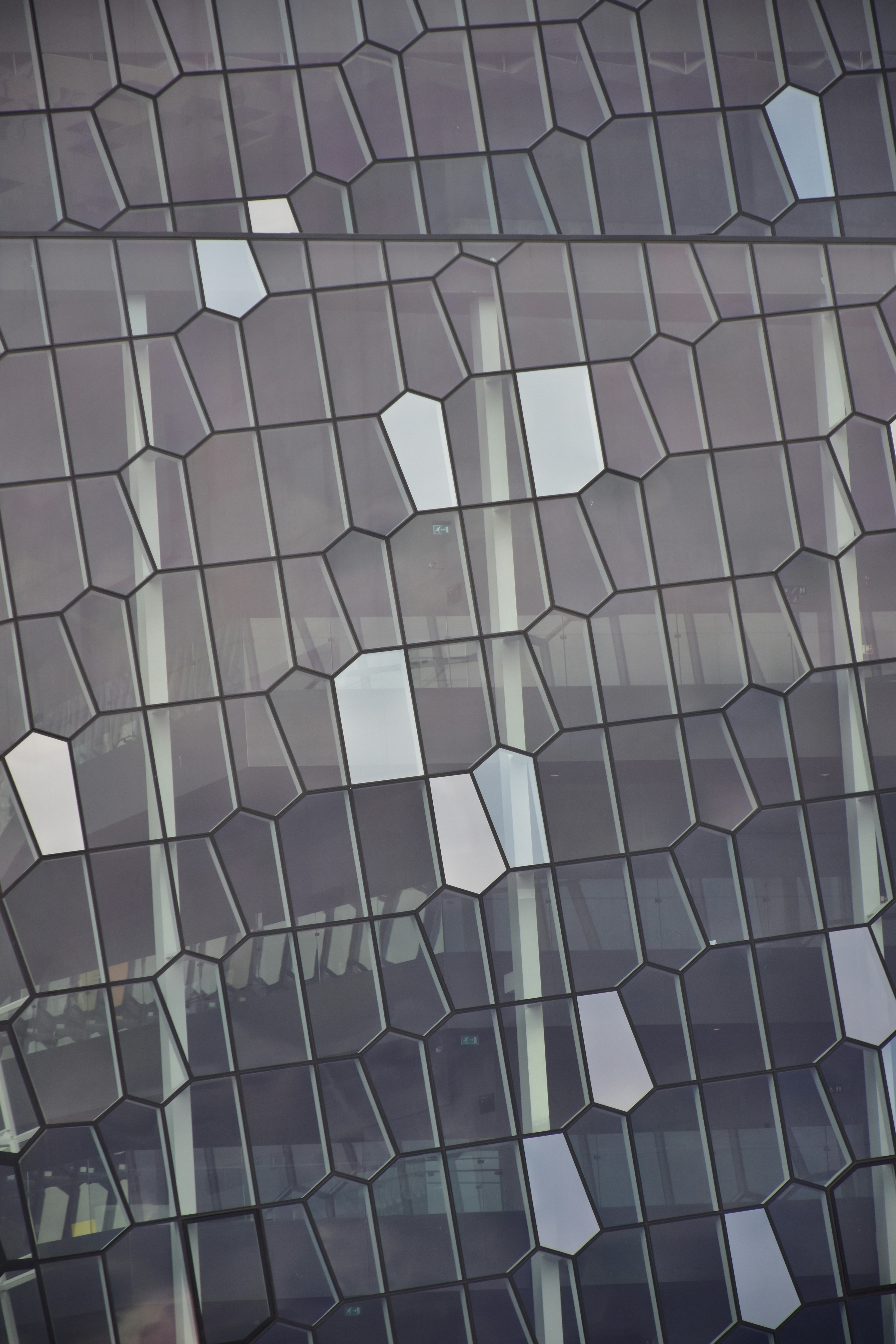 Abstract view of a modern building facade featuring hexagonal glass panels reflecting light and creating a dynamic visual effect.