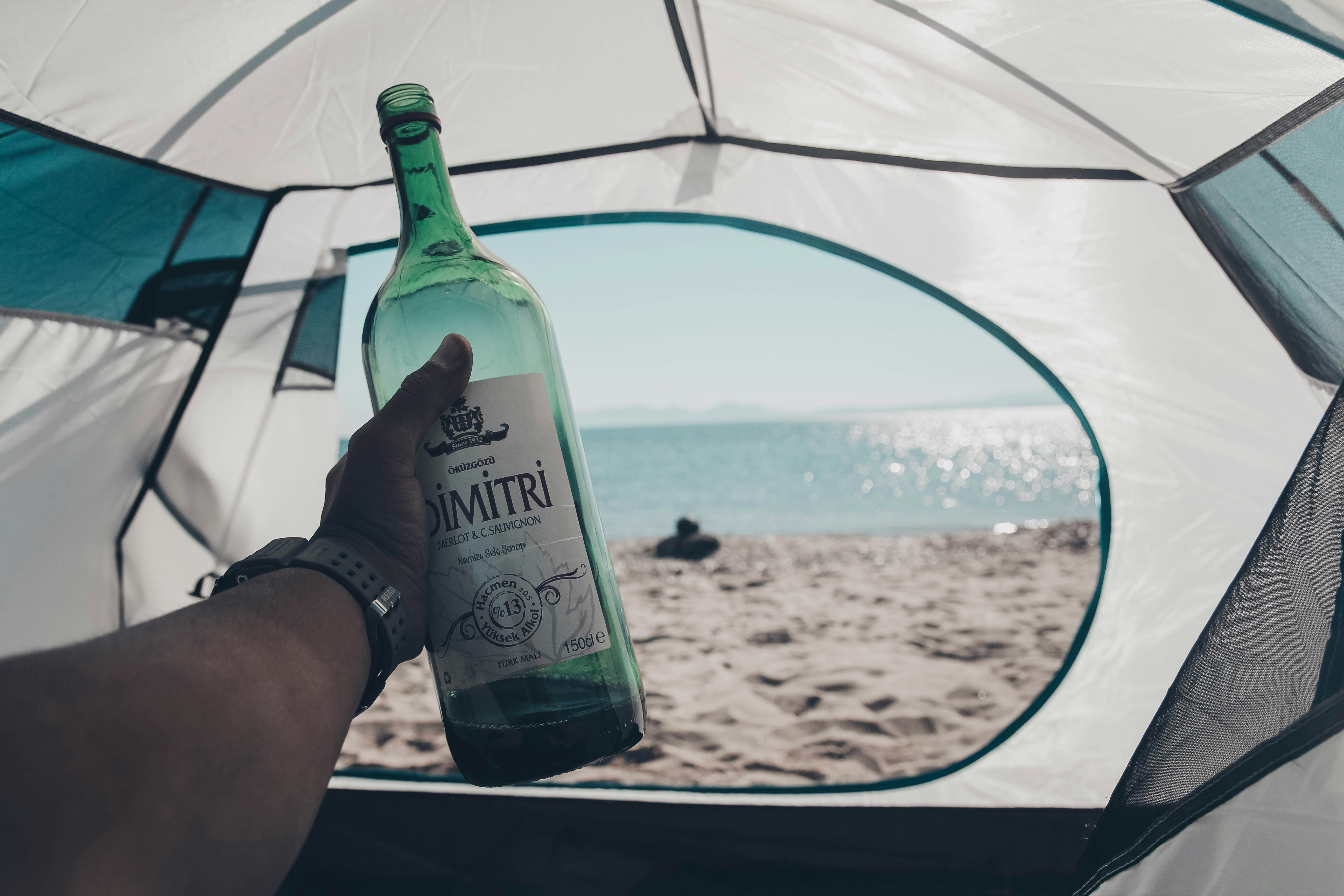 Beachfront Cheers: Bottle Reaches Out from a Tent Window