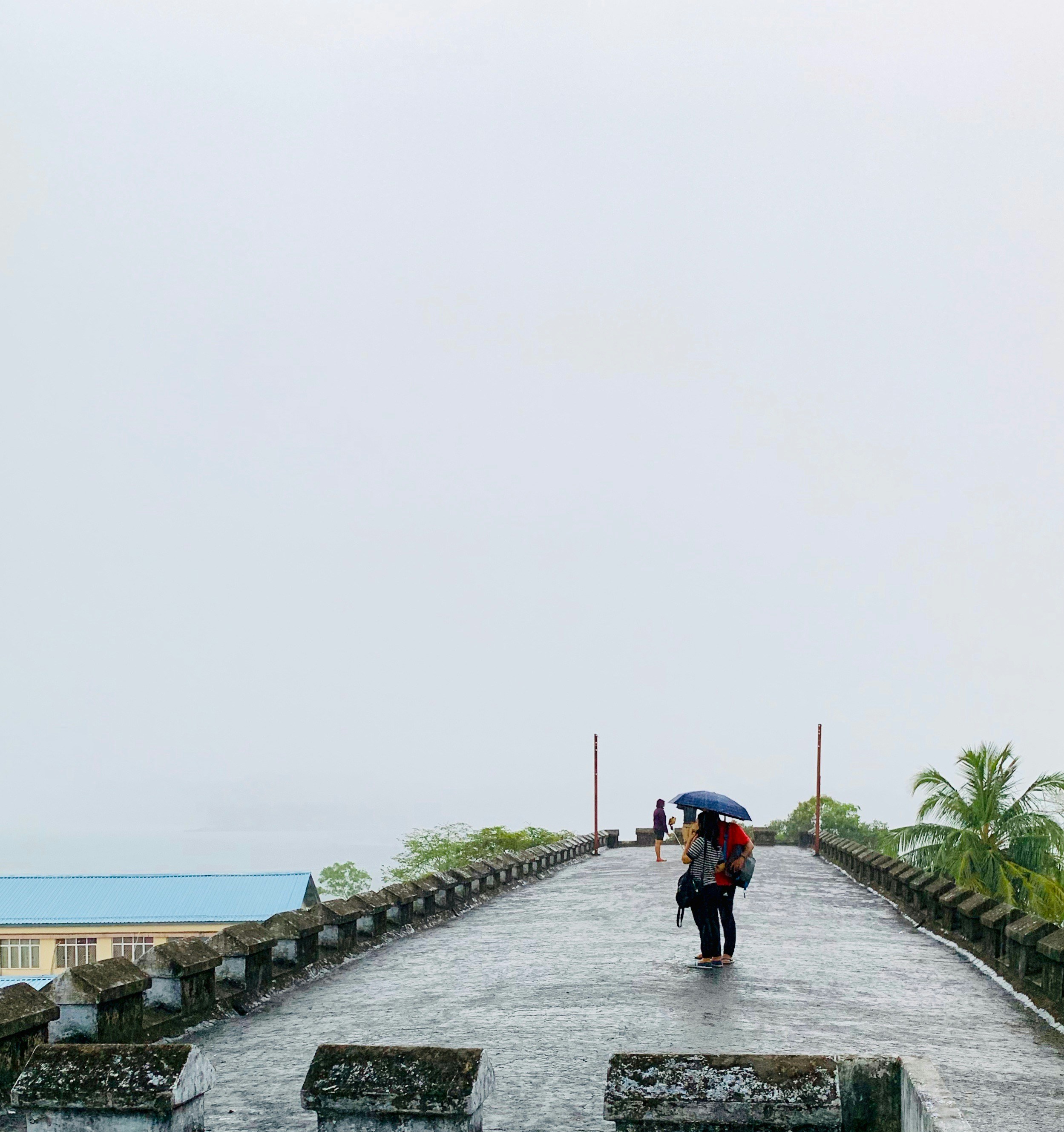Umbrella Crossing the Rain-Washed Pier Toward the Distant Mist