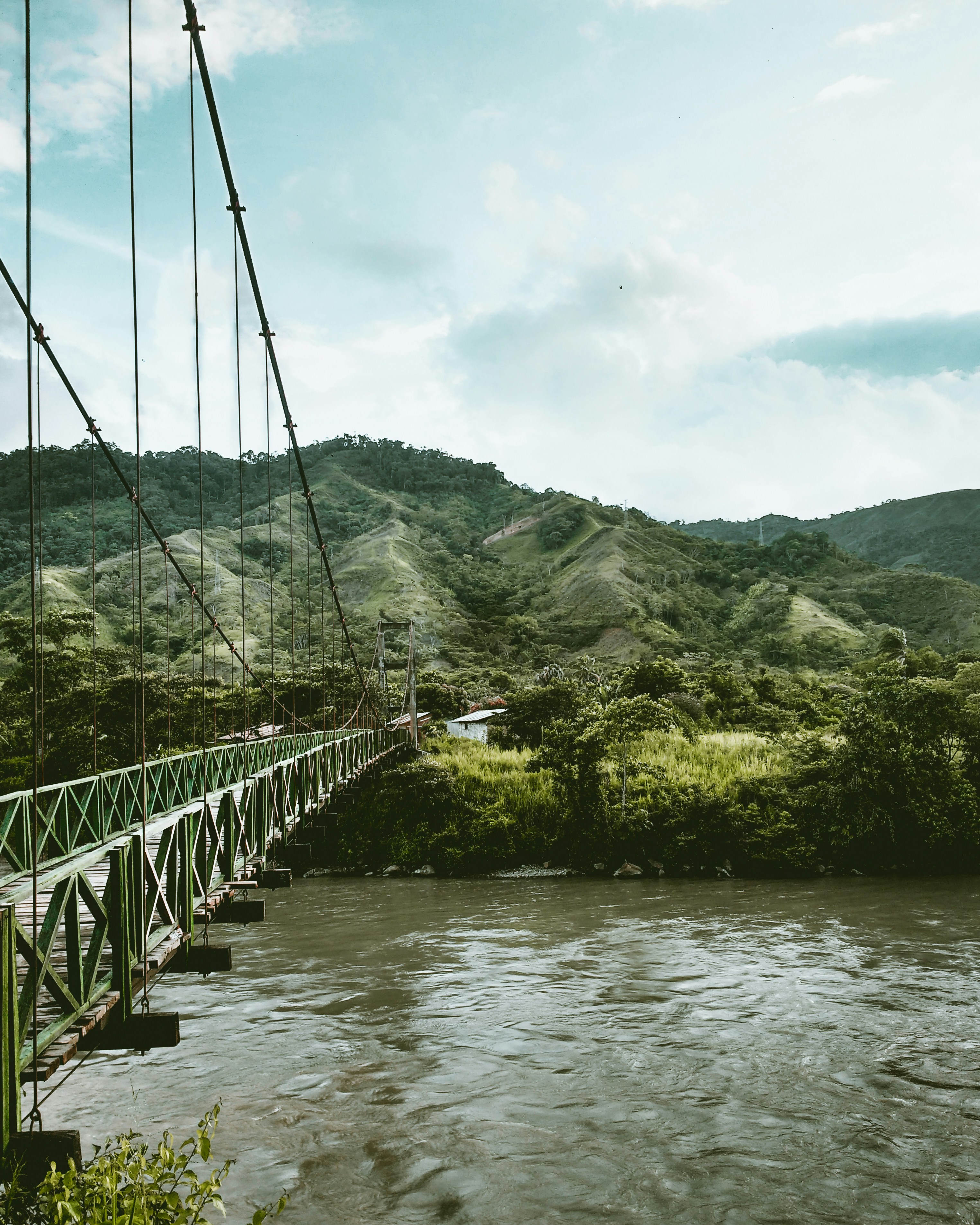 Suspended Path: A Riverside Suspension Bridge into Verdant Valleys
