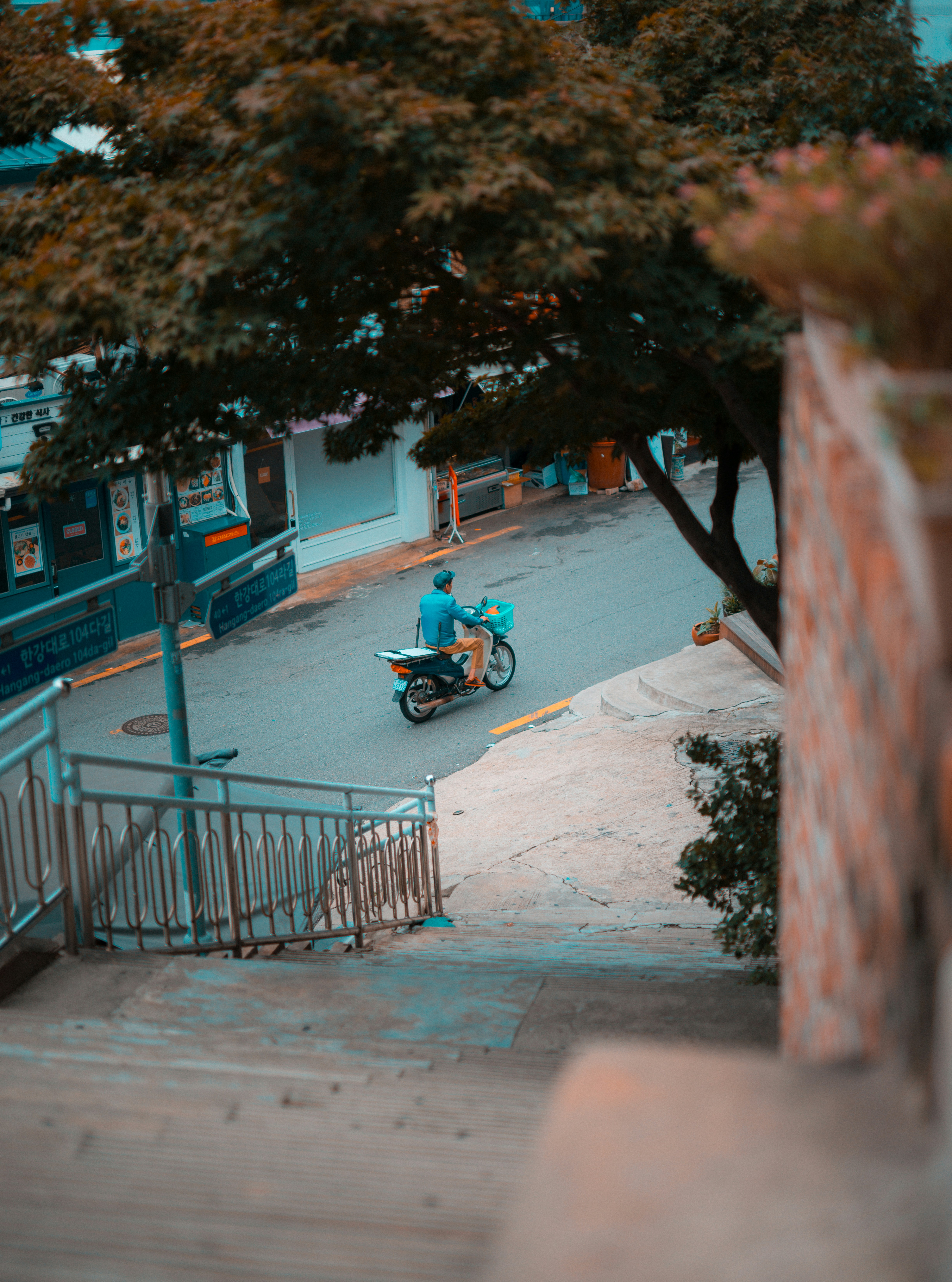 Blue-Shirt Rider on a Quiet City Street Framed by a Stairwell