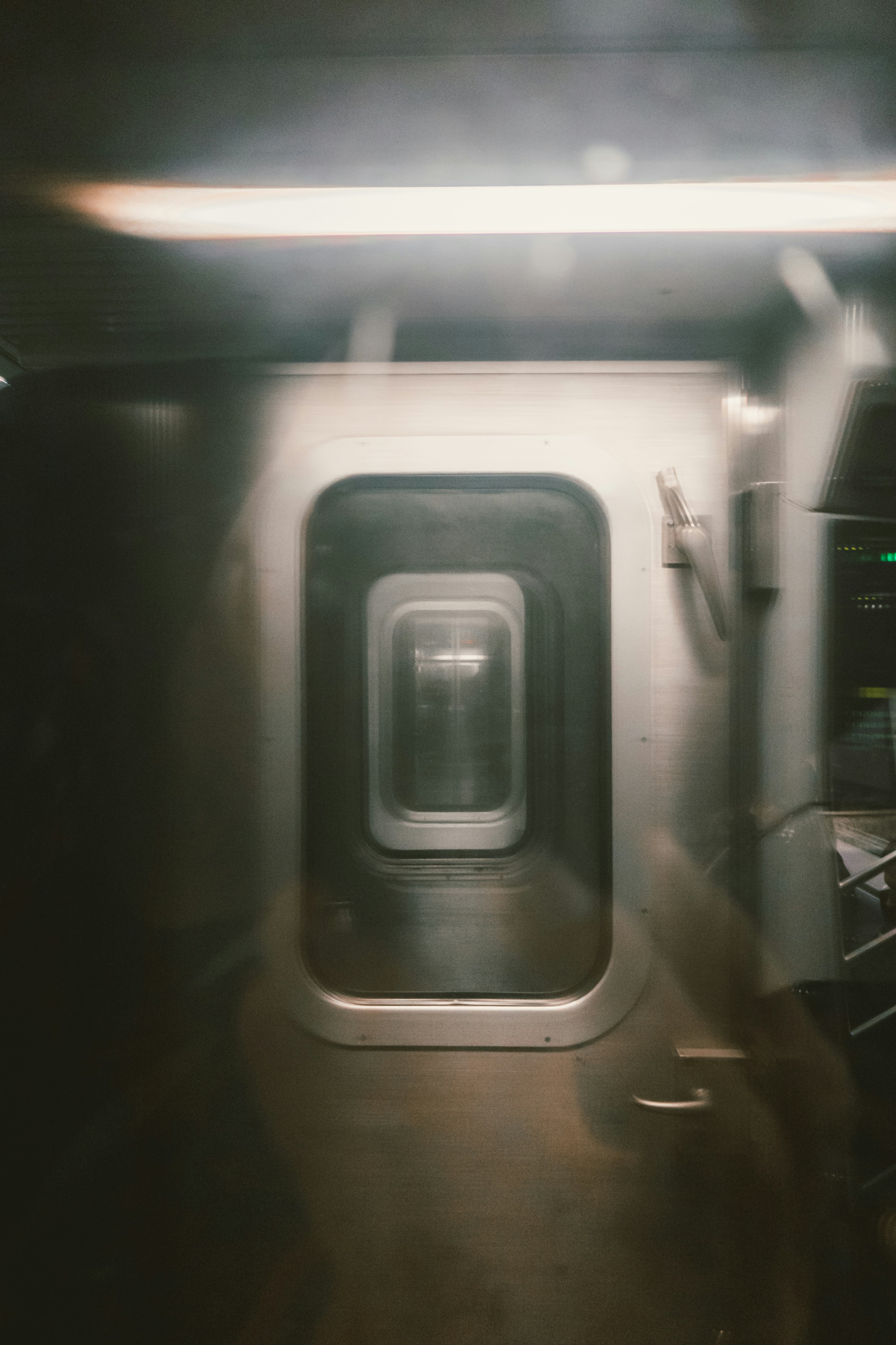 A series of metallic doorways receding into the distance, creating a sense of depth and reflection. The image captures a moment within a train corridor.