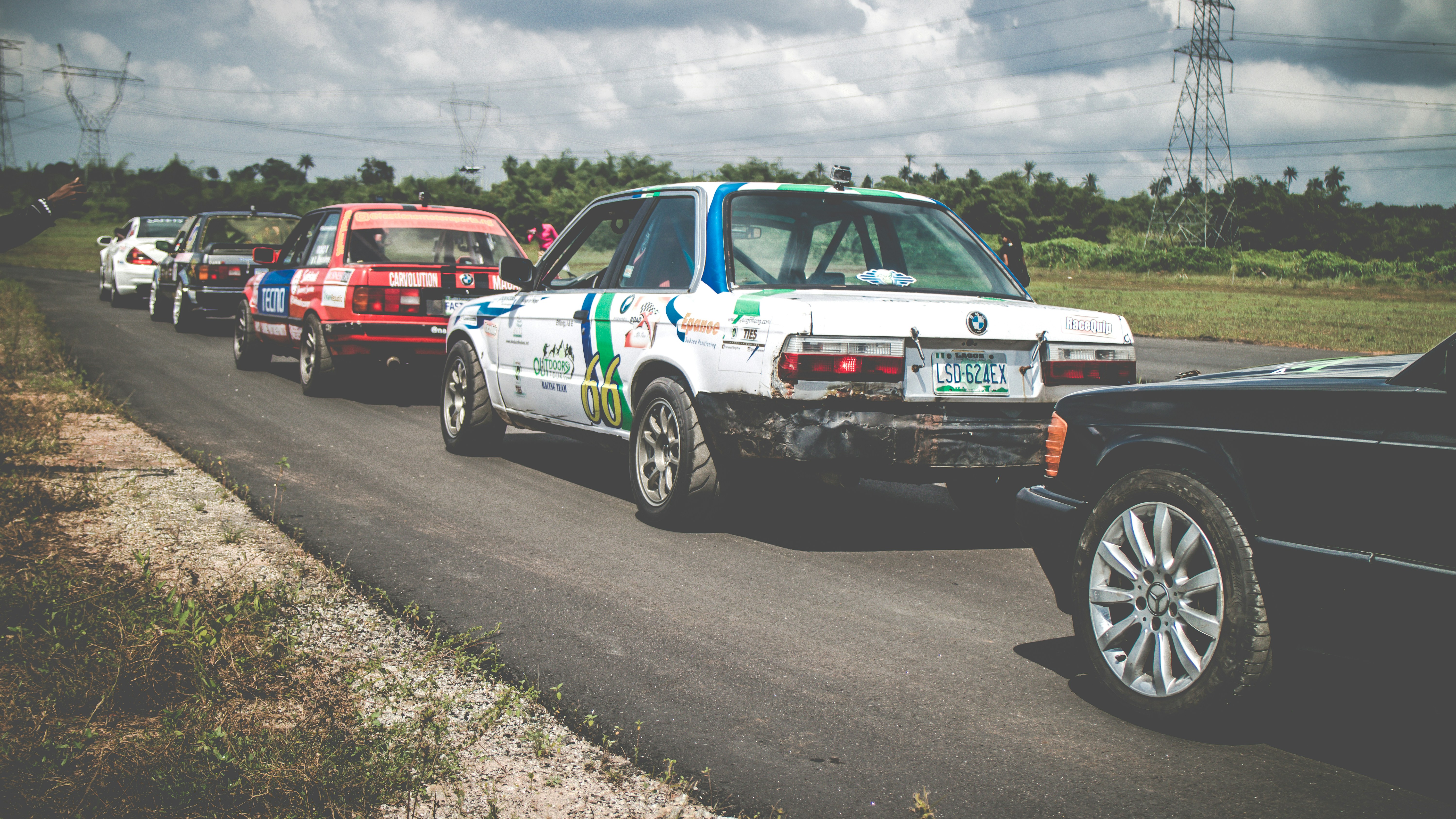 Backroad Rally Lineup: Cars Parade Toward the Distant Horizon