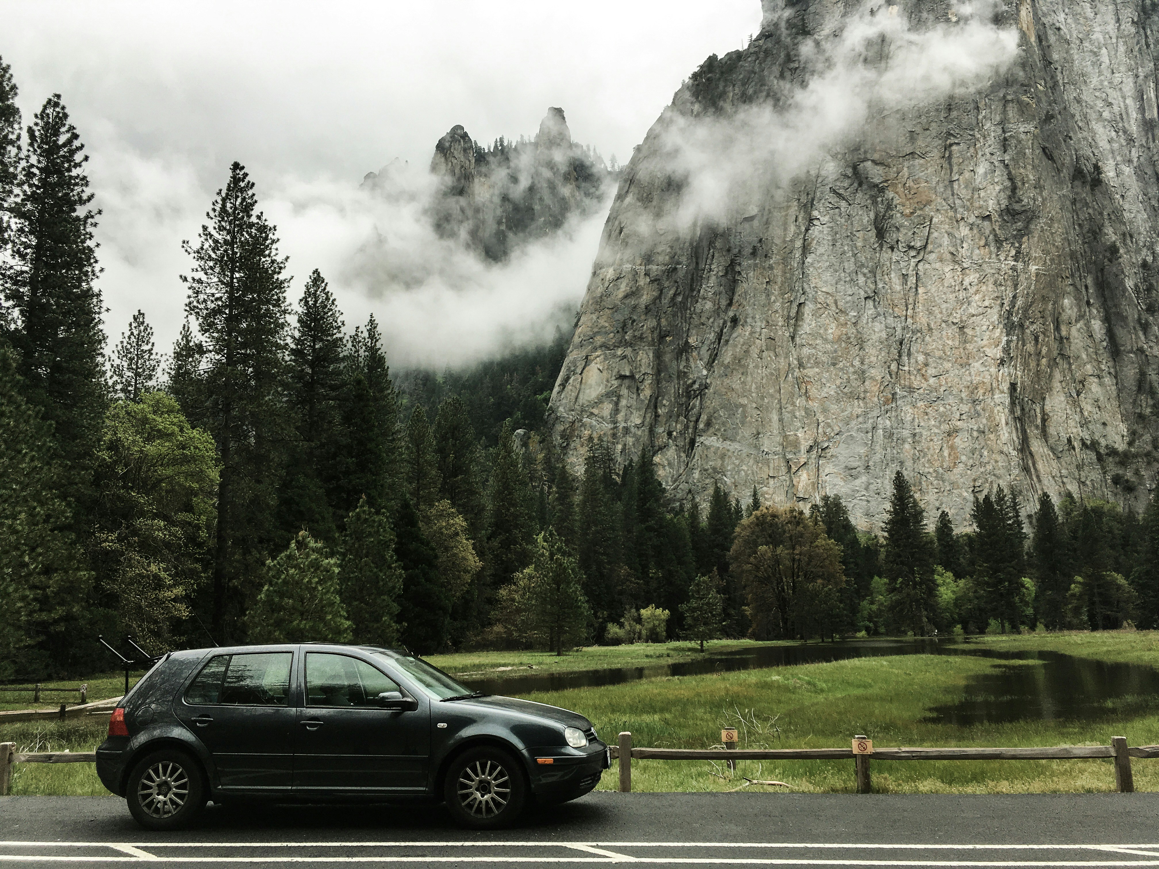 gray 5-door hatchback on the road near trees and mountain