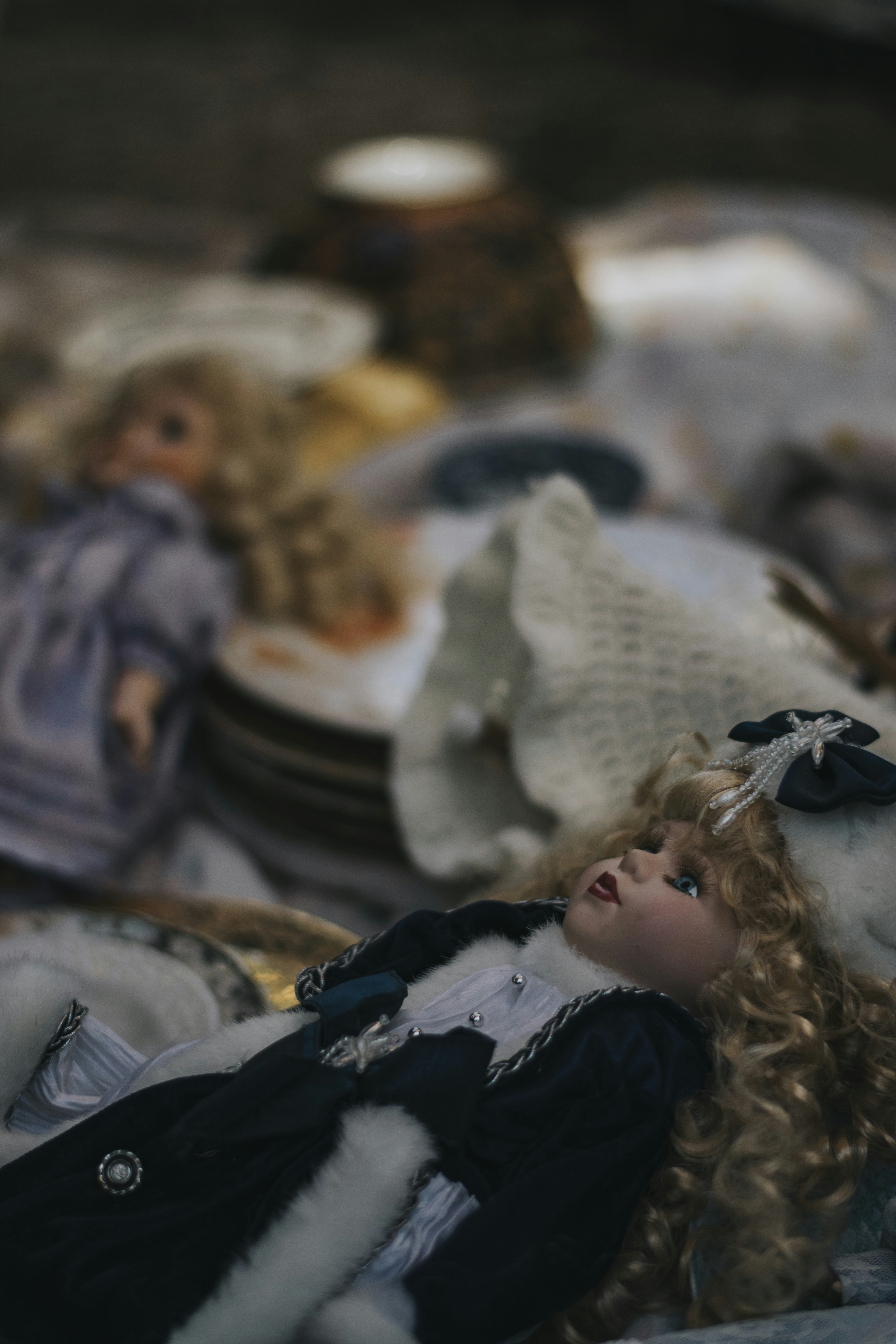 A vintage doll dressed in elegant attire rests among delicate china and lace, evoking memories of a bygone era.