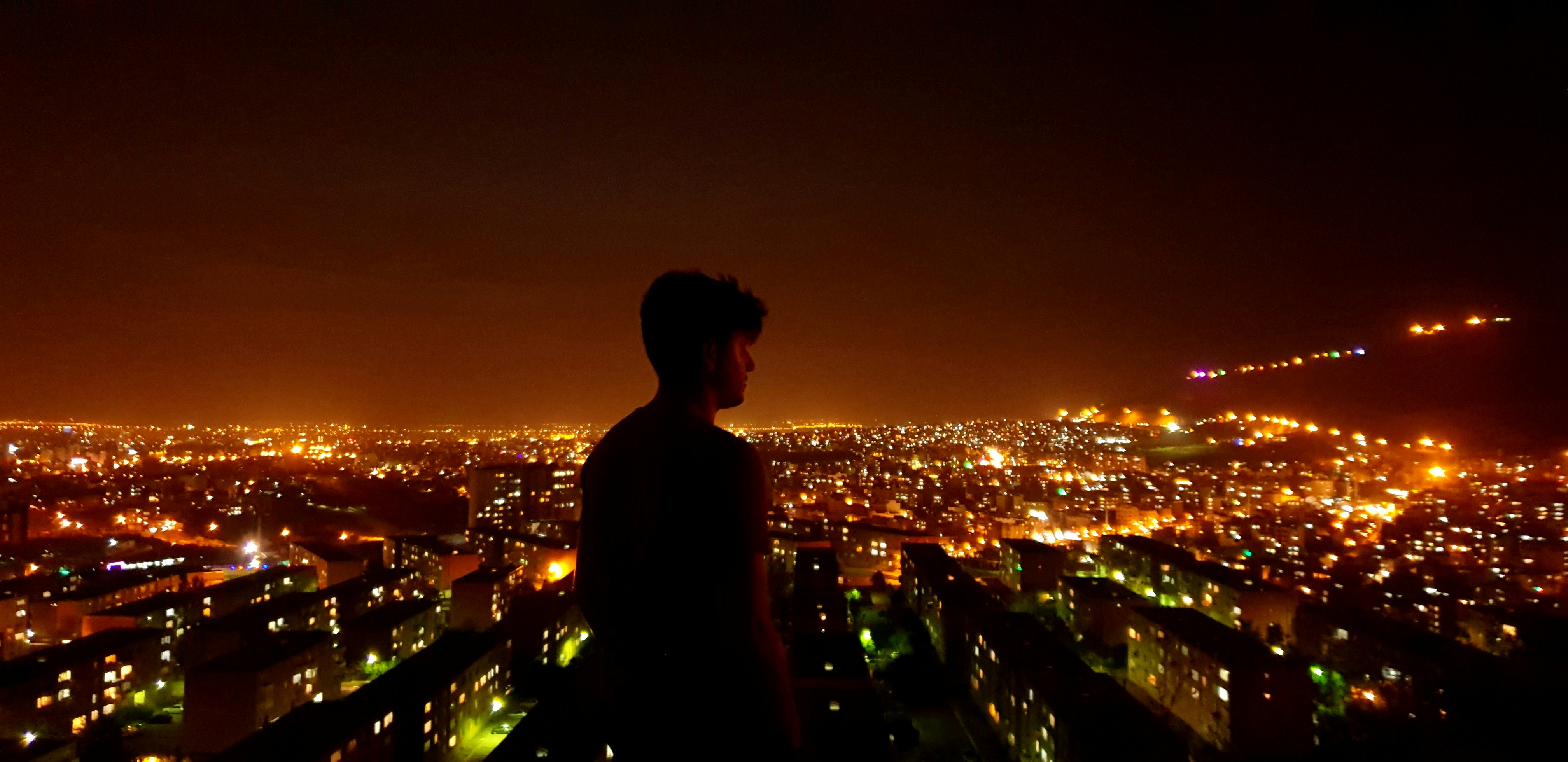 Man standing looking at his right near city during night photo – Free ...