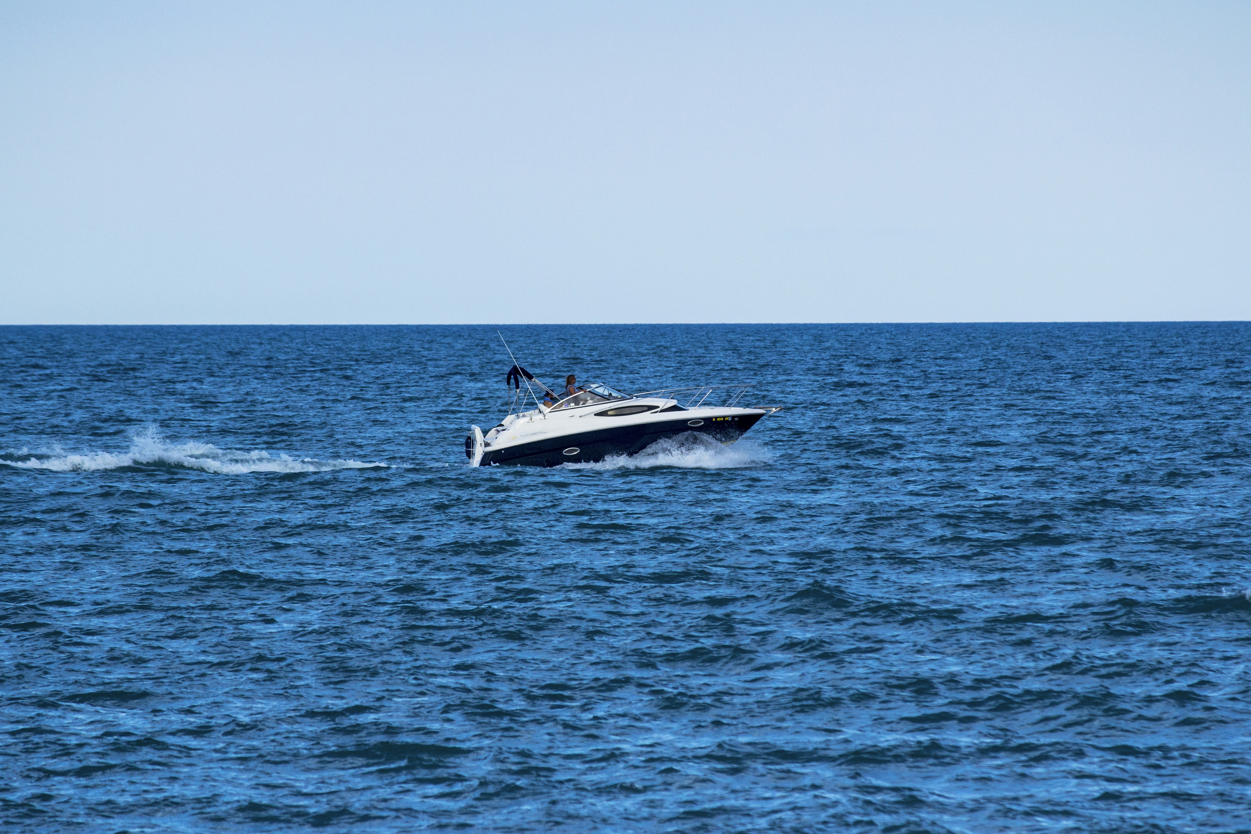 White speedboat cruising through deep blue sea under clear sky.