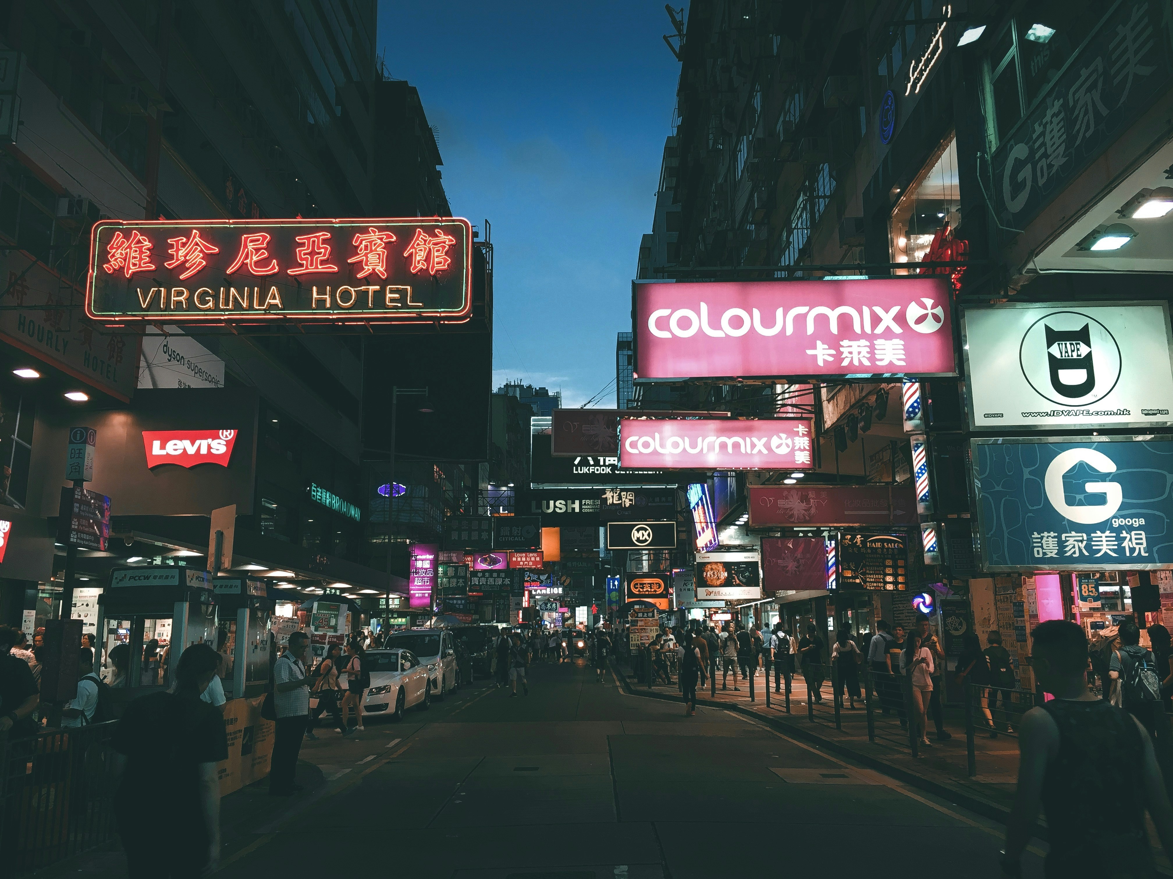 Crowd walking on pathway surrounded by buildings during night time ...