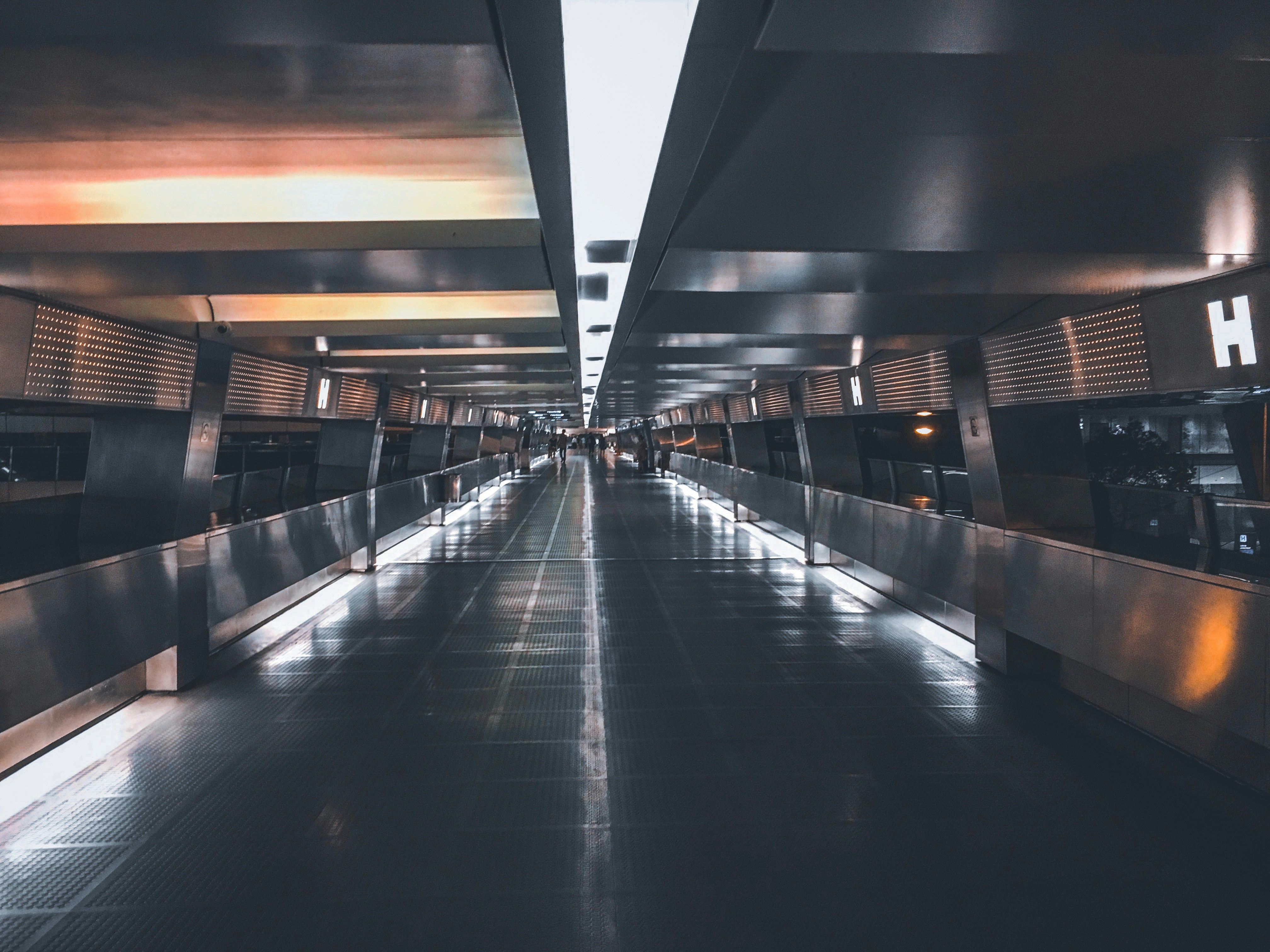 Dimly lit hallway with reflective metal surfaces and overhead lighting.