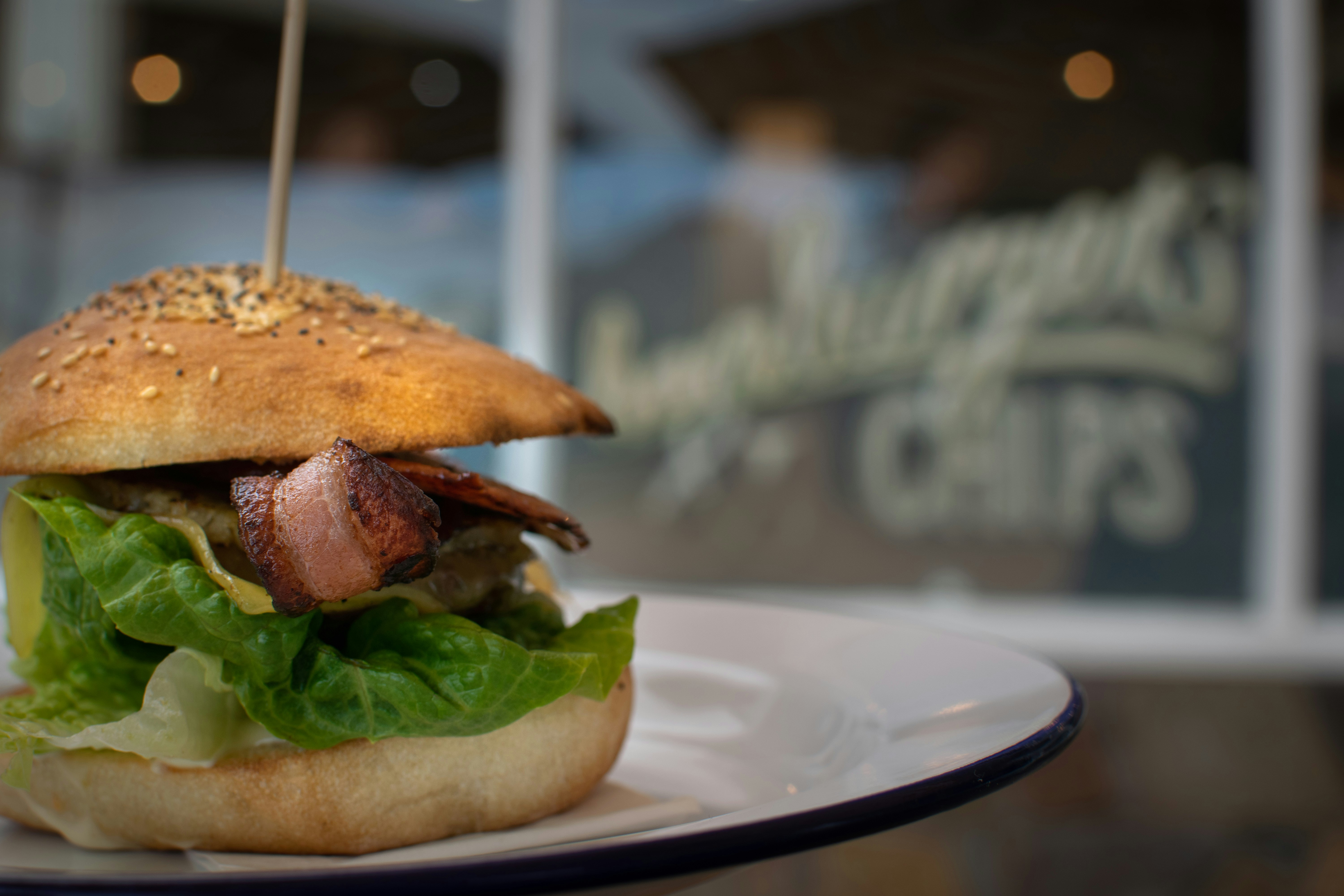 Spotlit Bite: A Crisp Close-Up of Bacon, Greens, and Sesame Bun